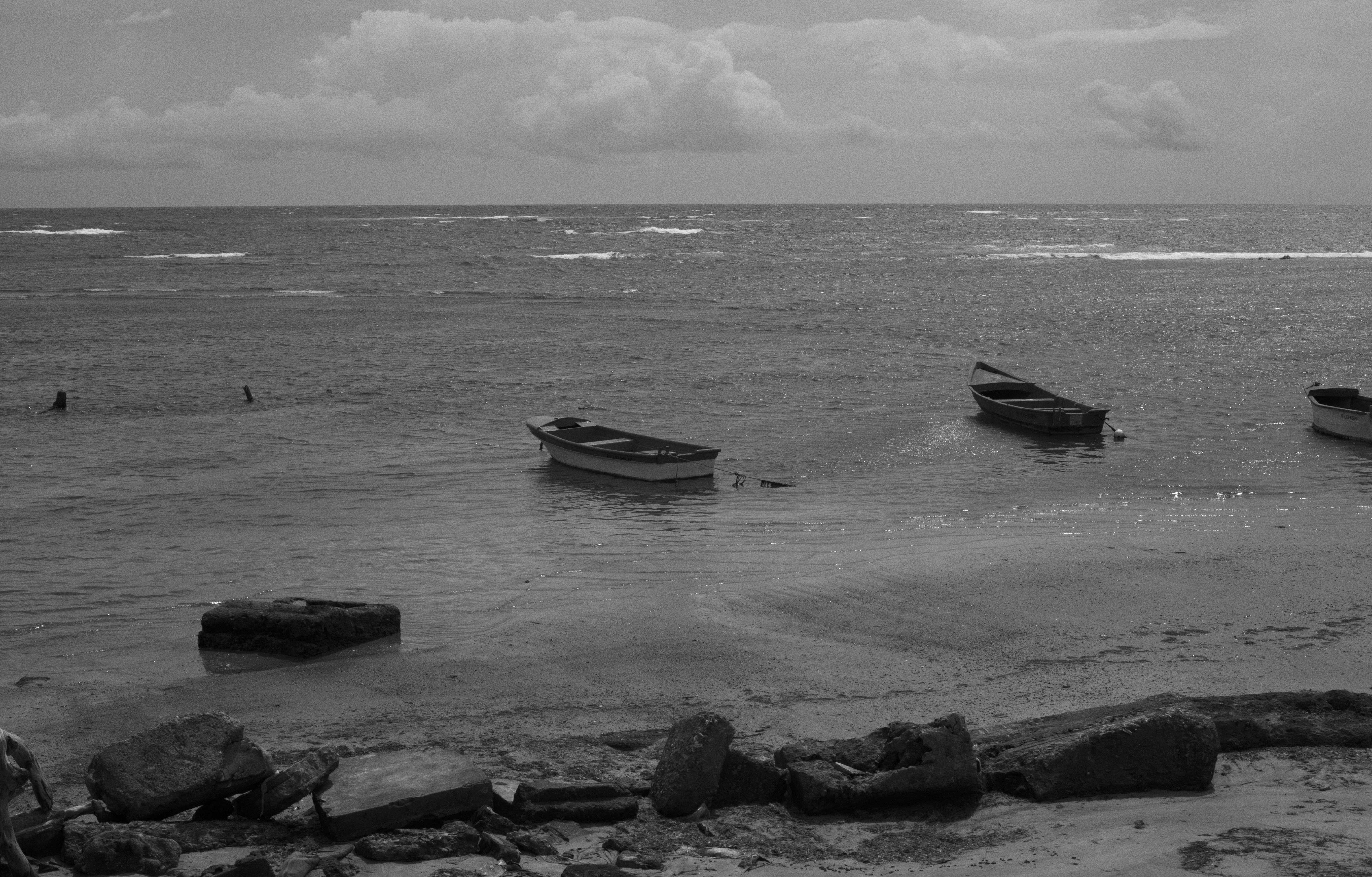 Boats rest on a tranquil sea under a cloudy sky.