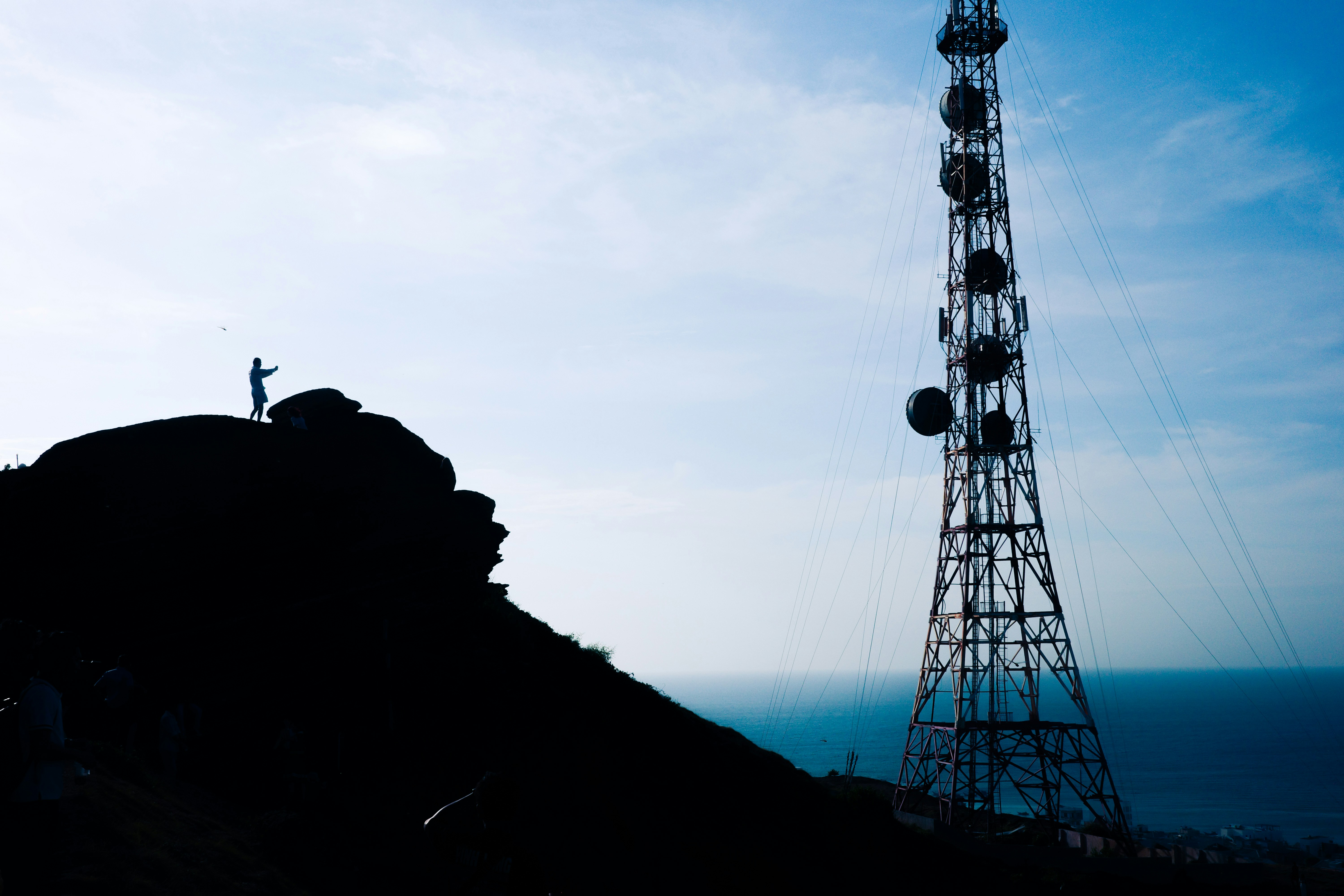 A person stands on hill beside a radio tower.