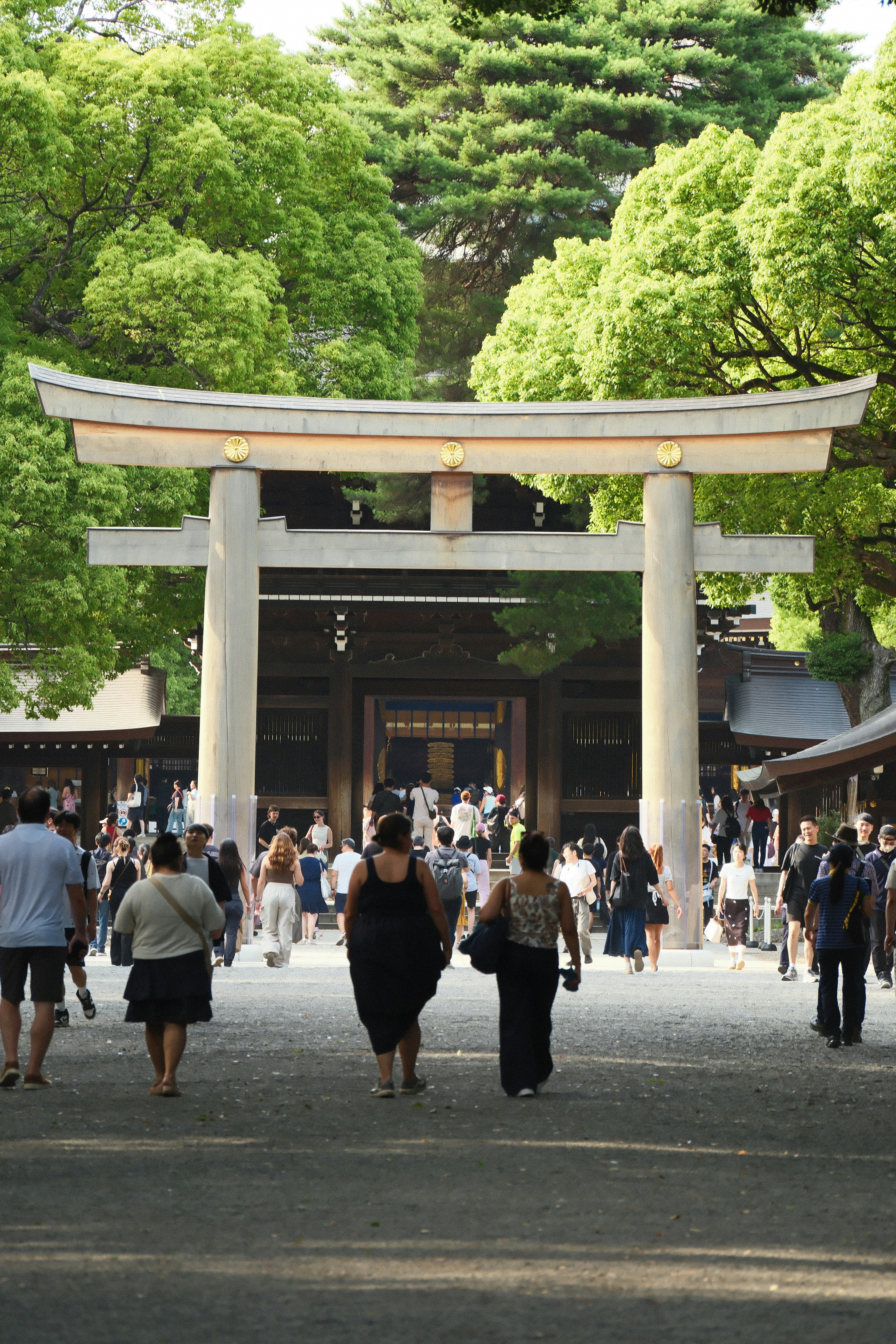 People walk towards a japanese shrine entrance.
