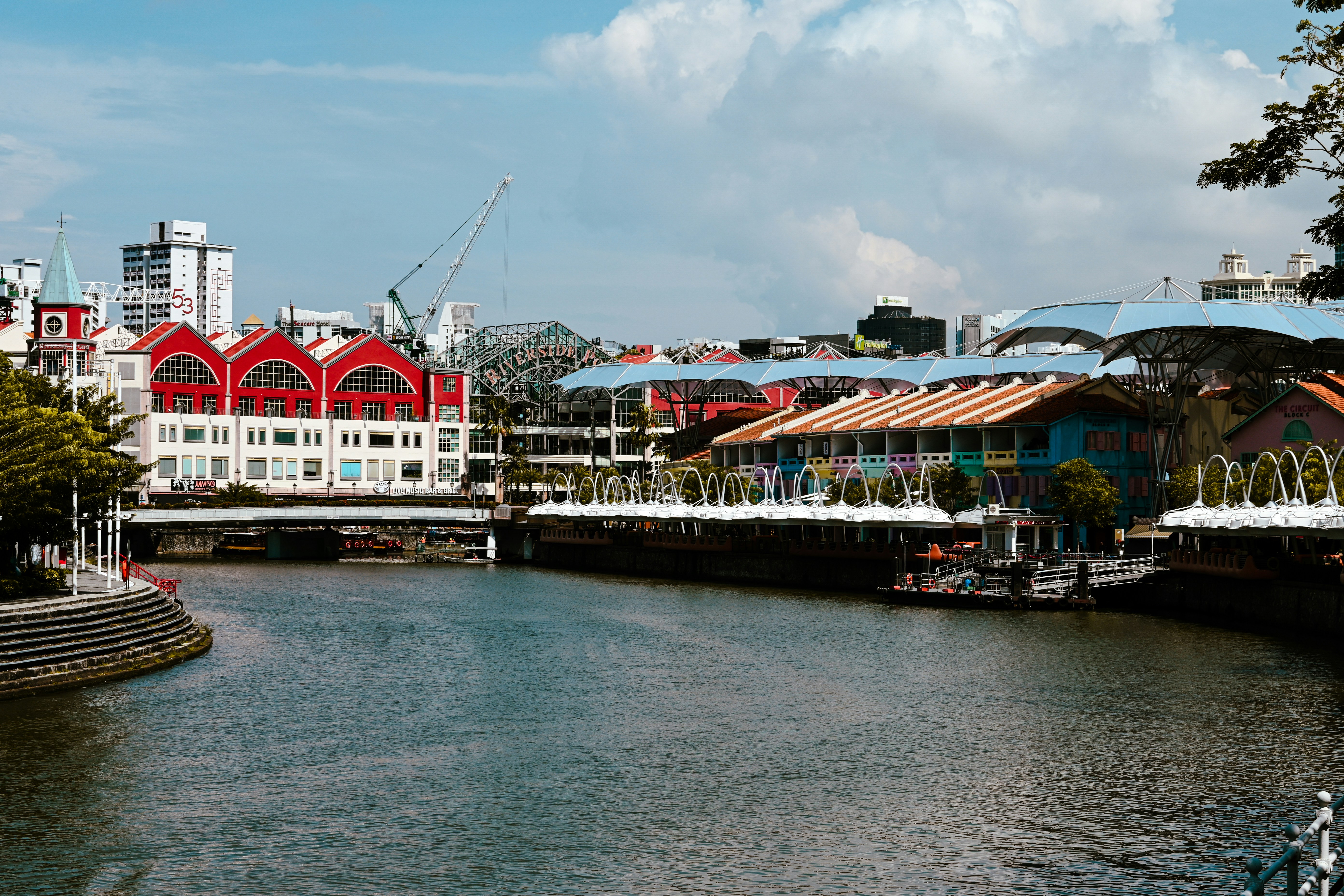 Vibrant waterfront scene showcasing colorful buildings and modern canopies along a serene river. A blend of urban architecture and nature's tranquility.