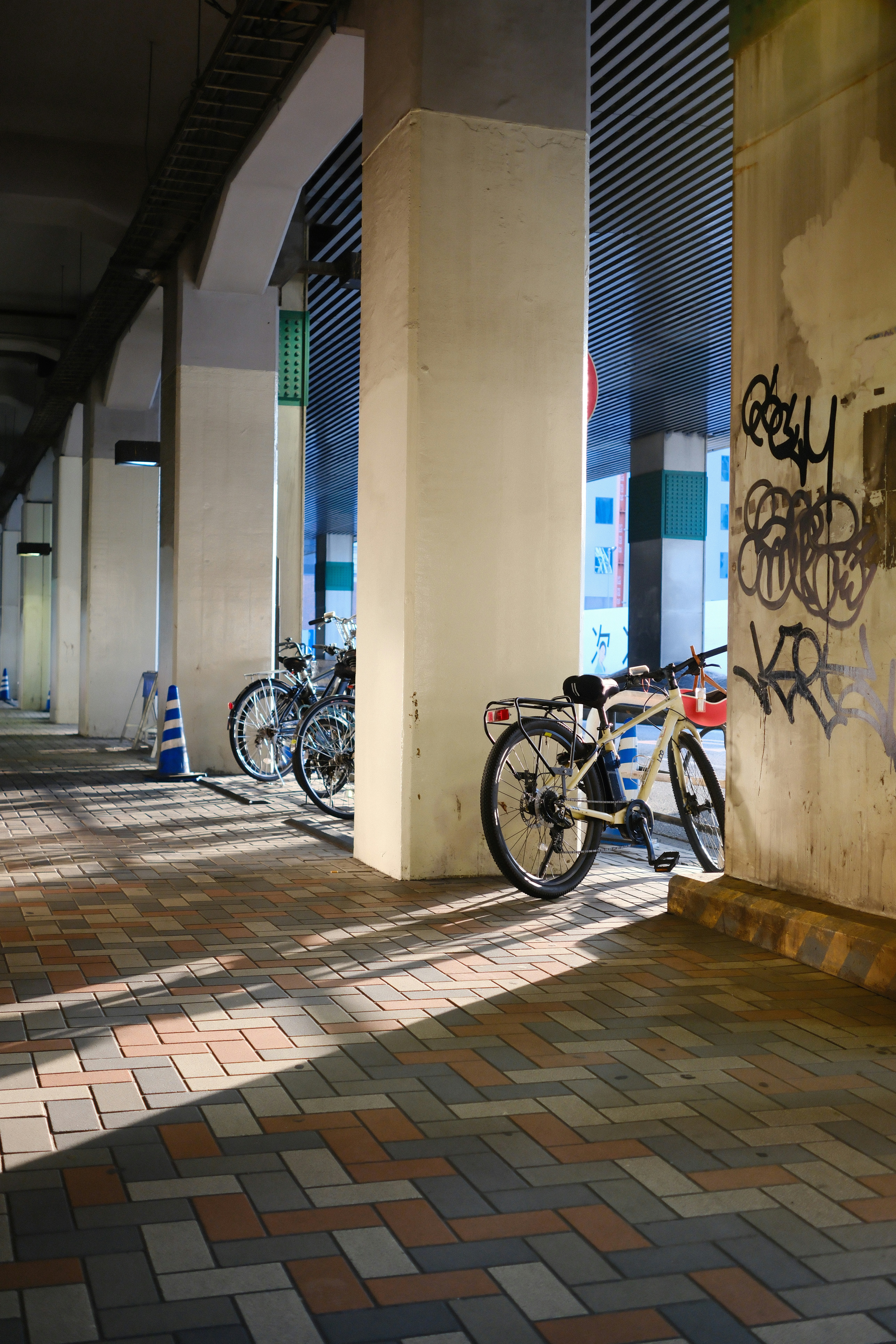 Underpass Eclipse: A lone bicycle between concrete columns and graffiti