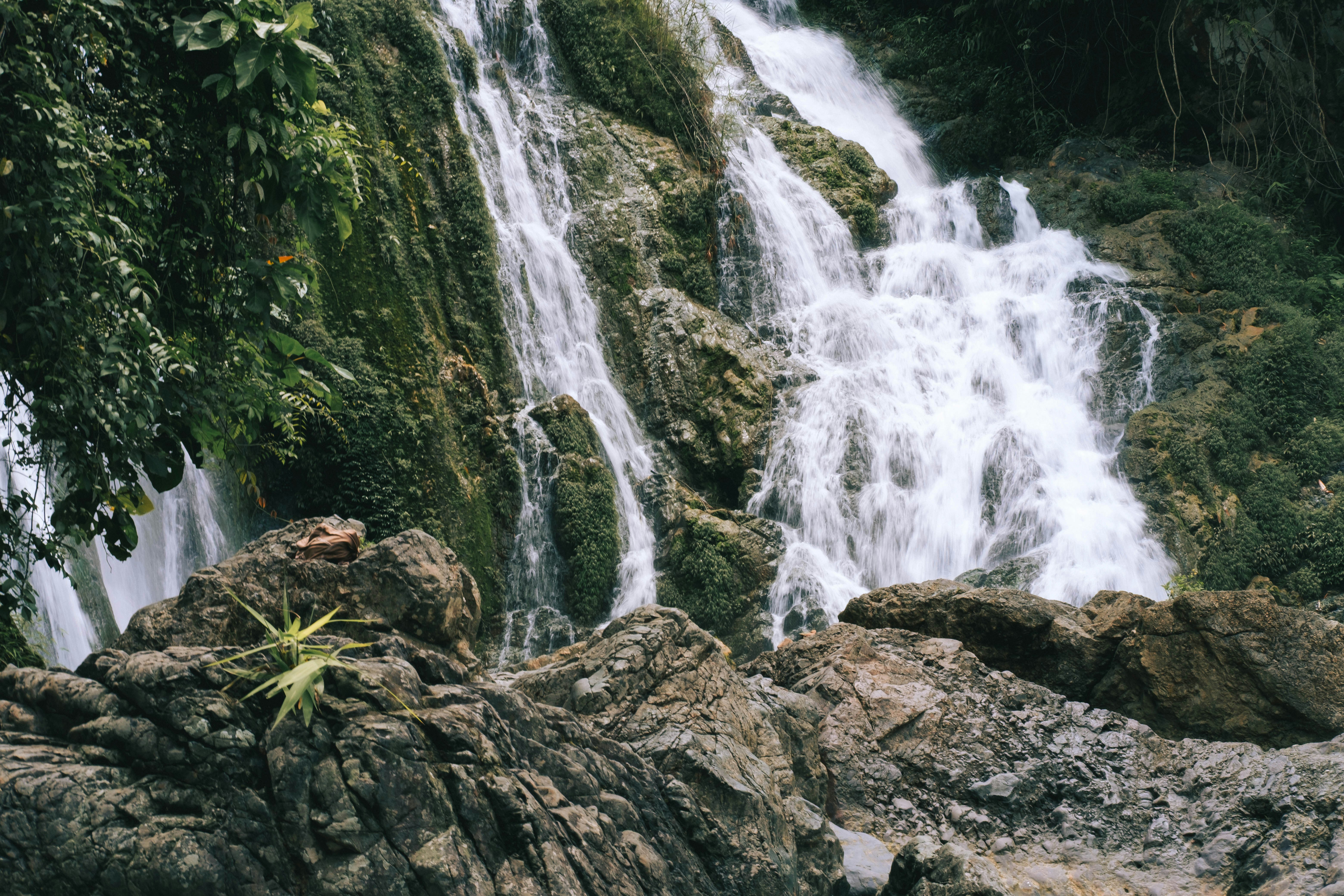 A cascading waterfall flows over rocky terrain.