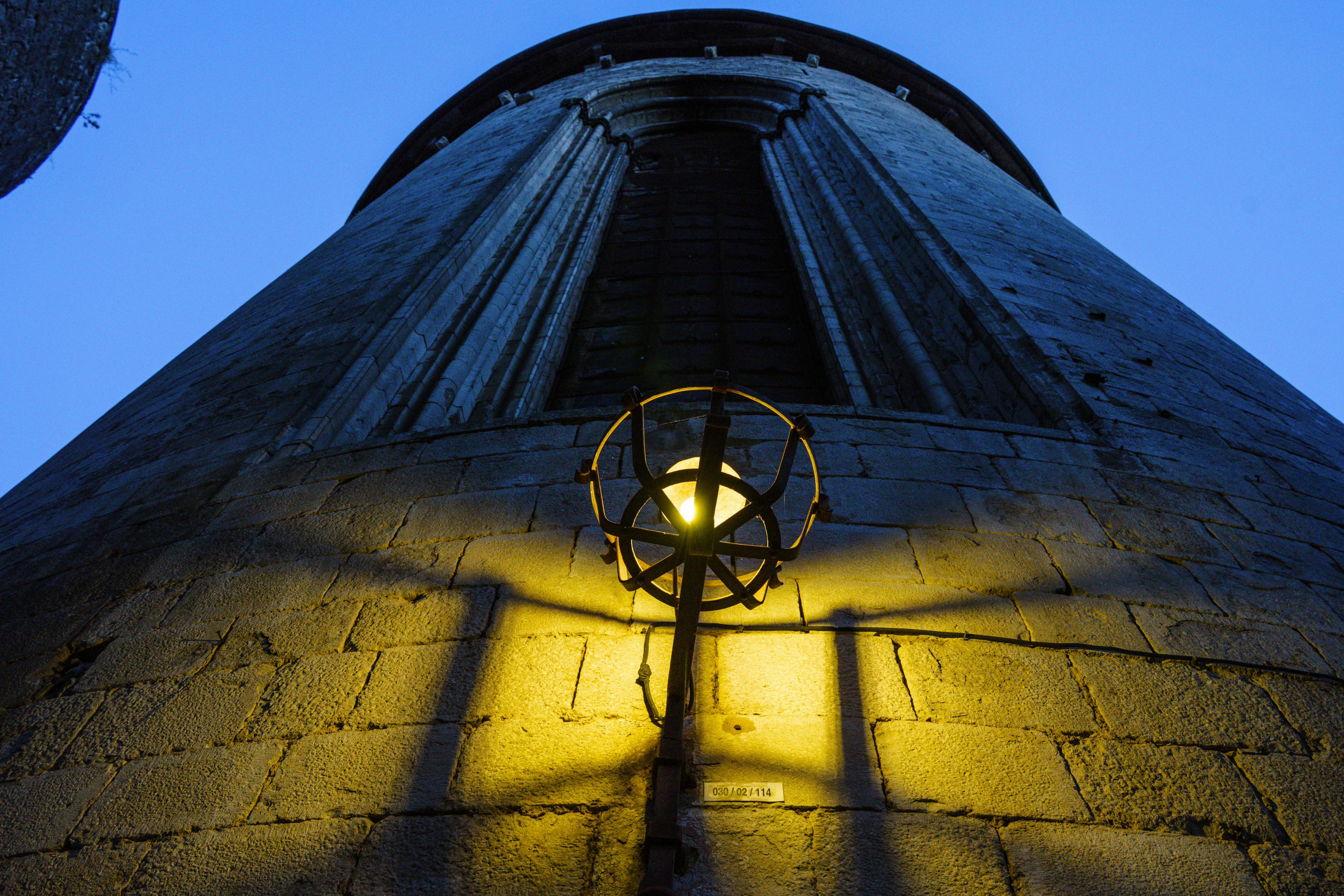 Midnight Beacon: Warm Lantern Elevates a Weathered Tower Under Cobalt Dusk