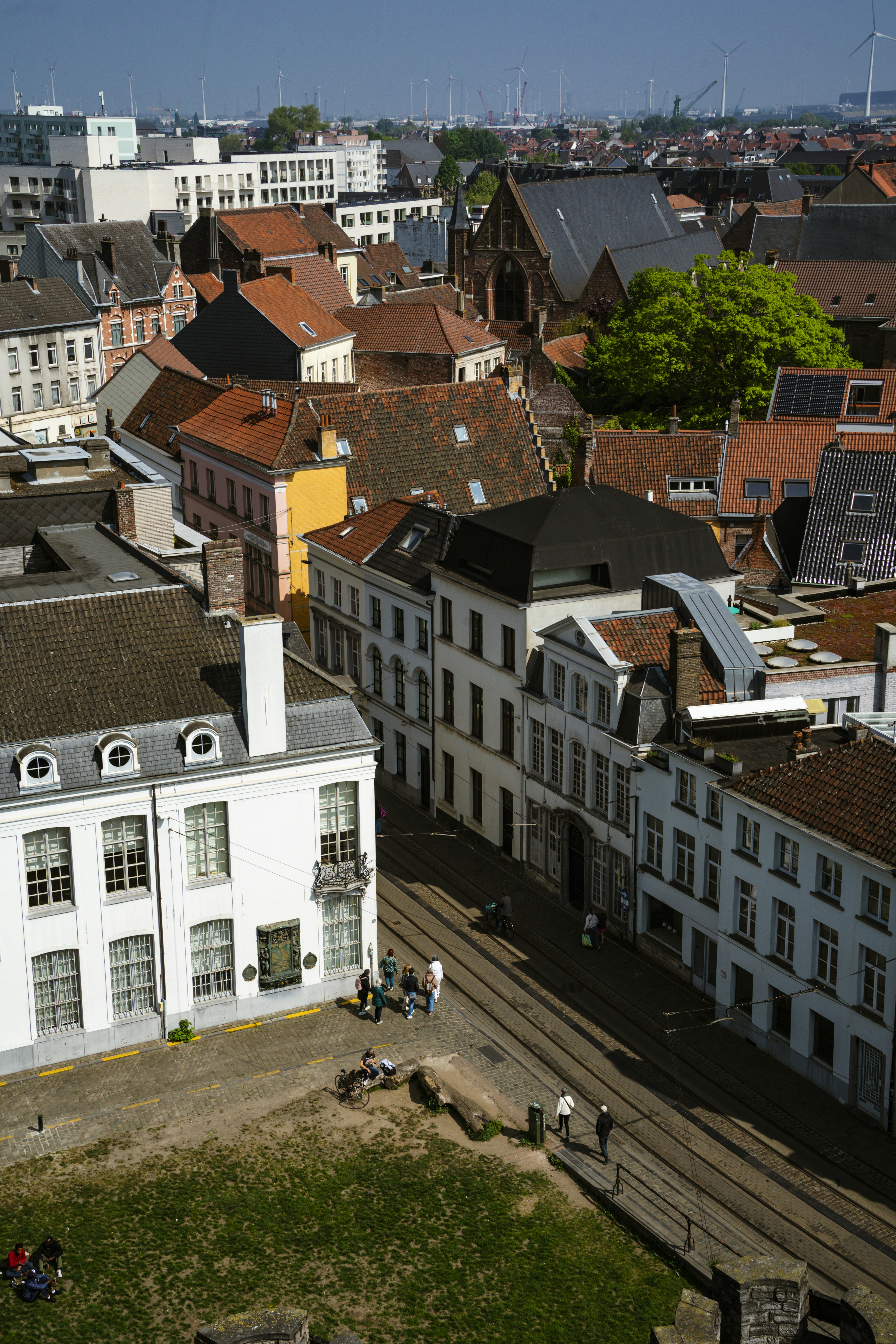 Overhead view of a vibrant cityscape showcasing a mix of historical and modern buildings, with people strolling along the street below.