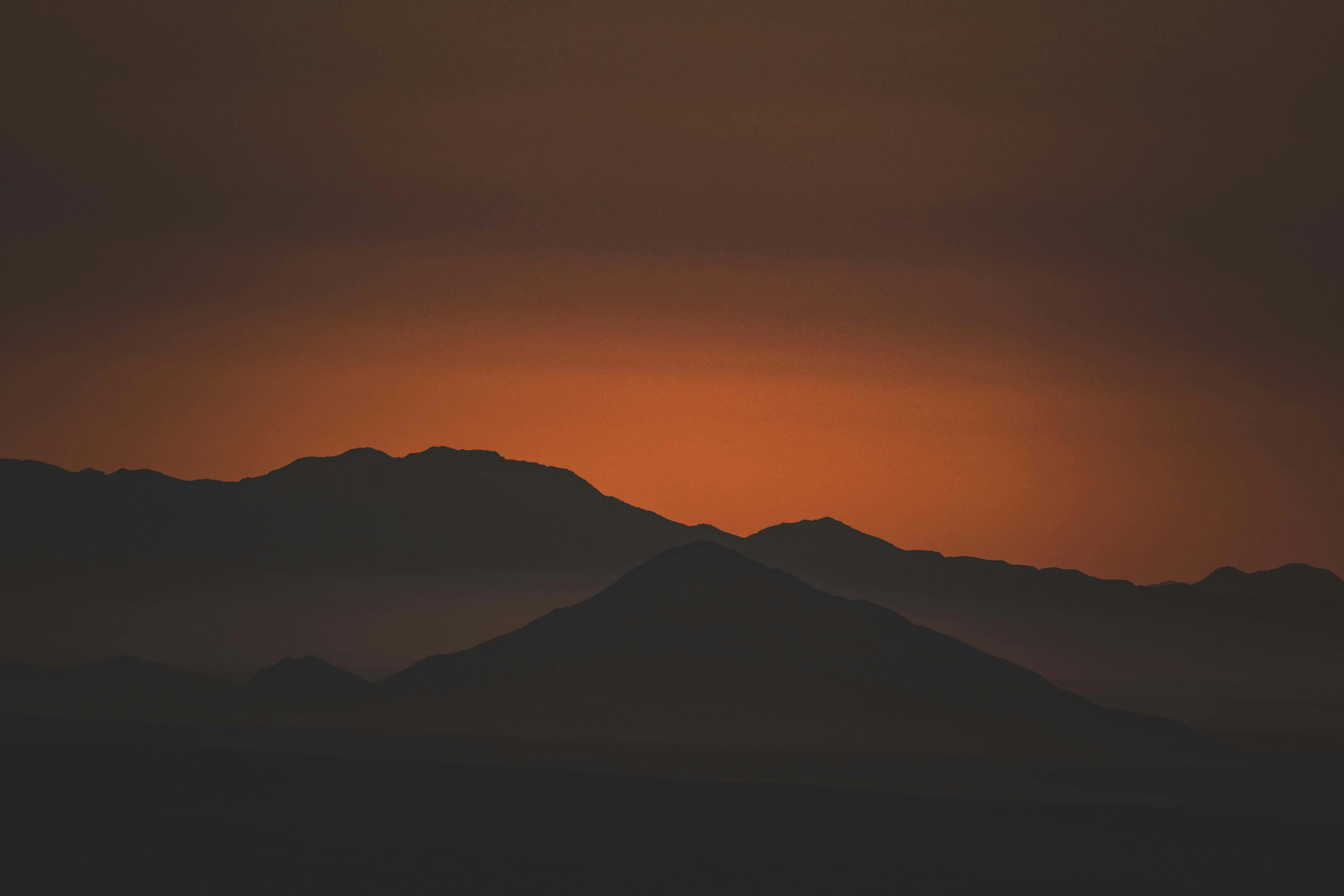 Mountains are silhouetted against a fiery sunset.