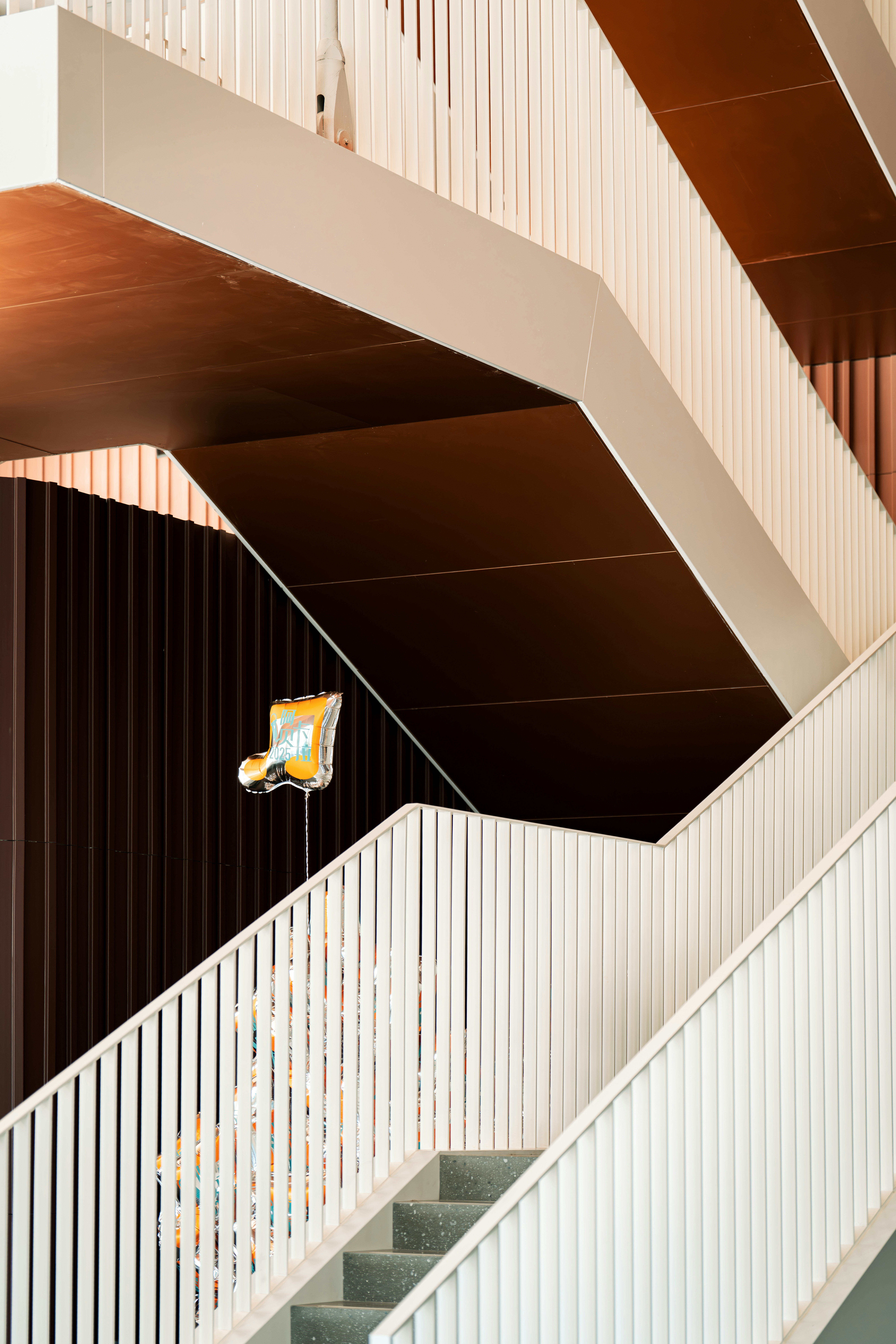 A balloon floats near a modern staircase.