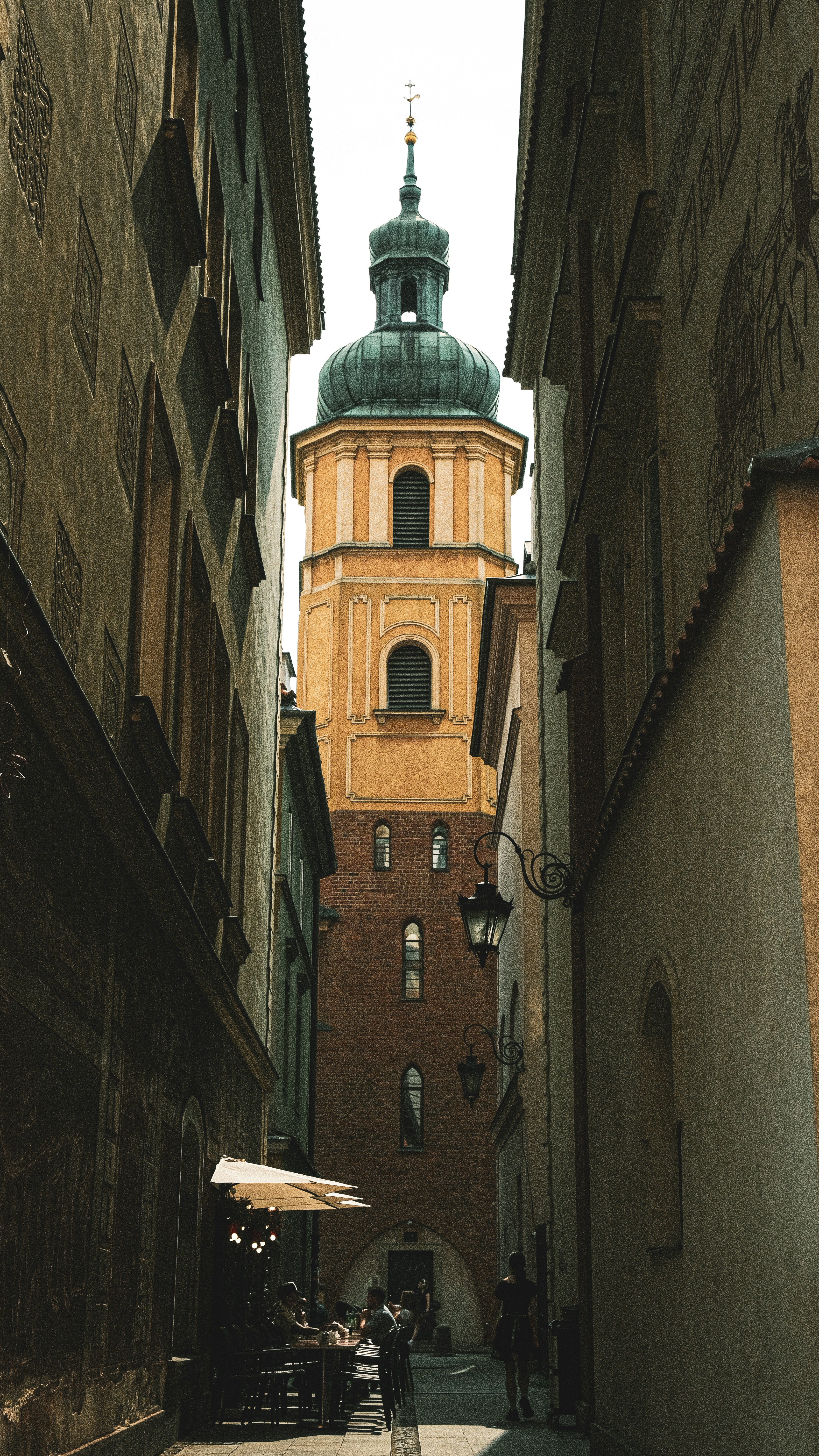 A tall tower visible through narrow buildings.