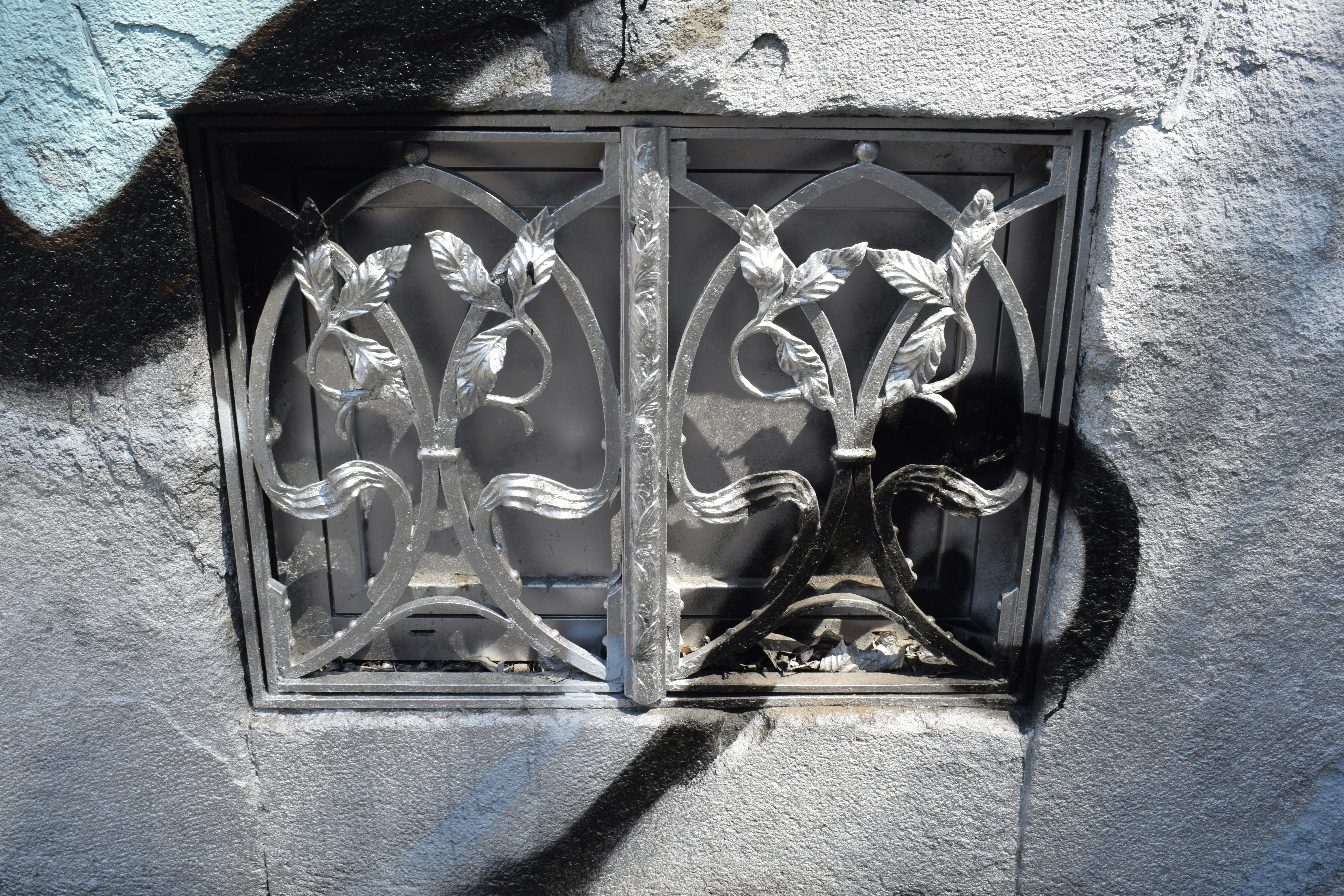Sunlit Grille: Weathered Ironwork Framed by Shadow and Wall Texture
