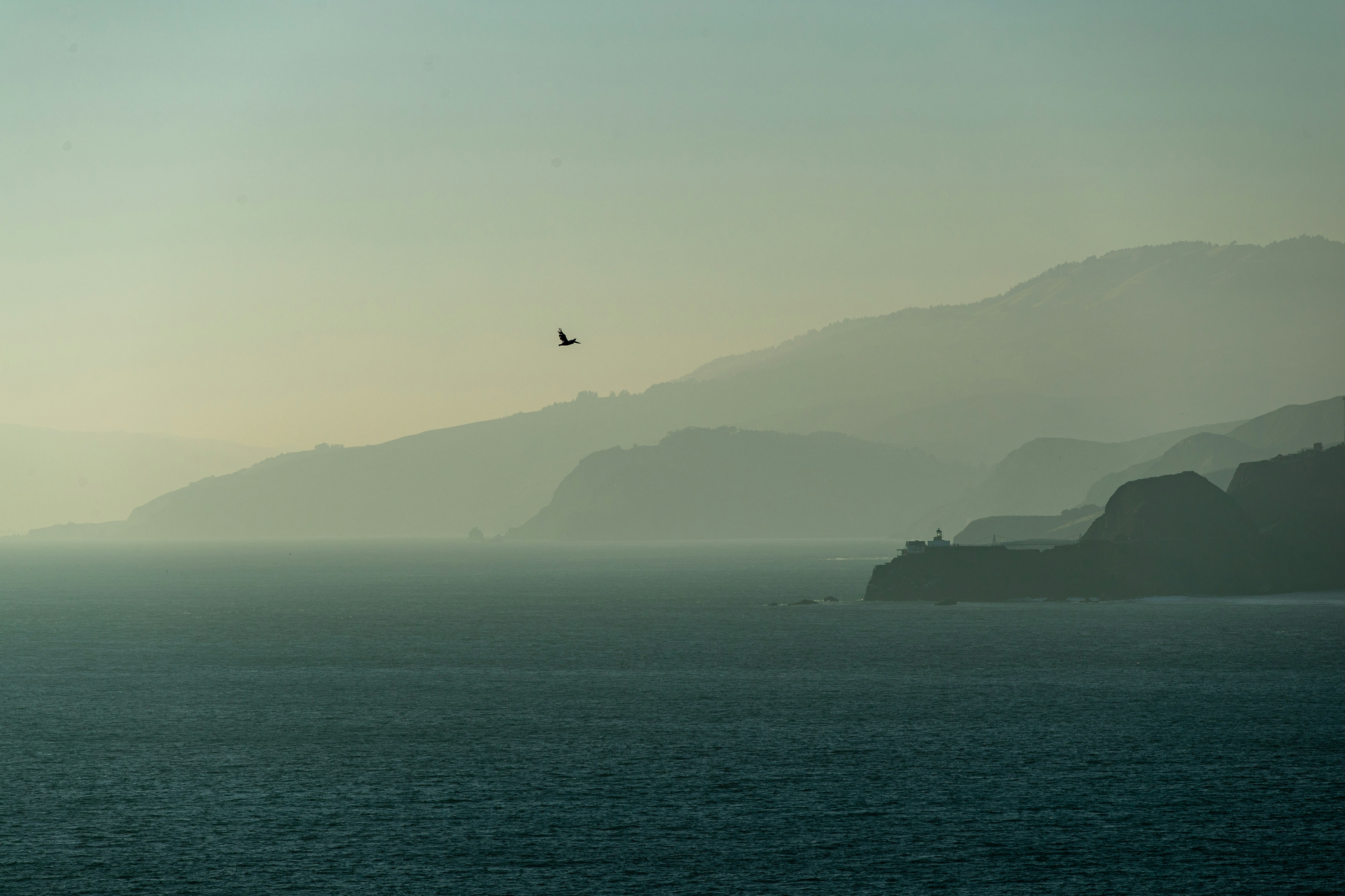 Hazy mountains appear over the sea in the distance.