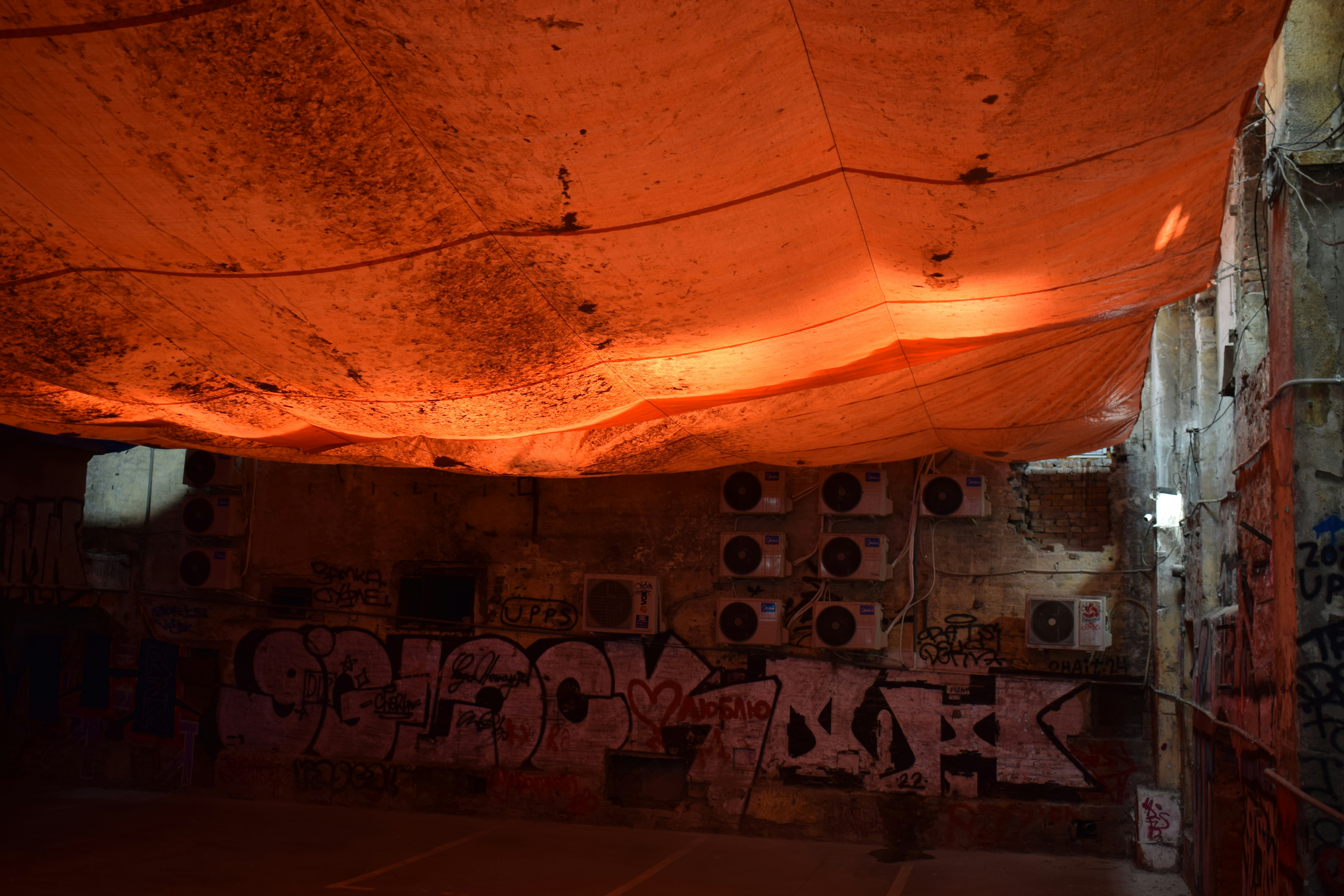 An alleyway with a canvas roof and graffiti.
