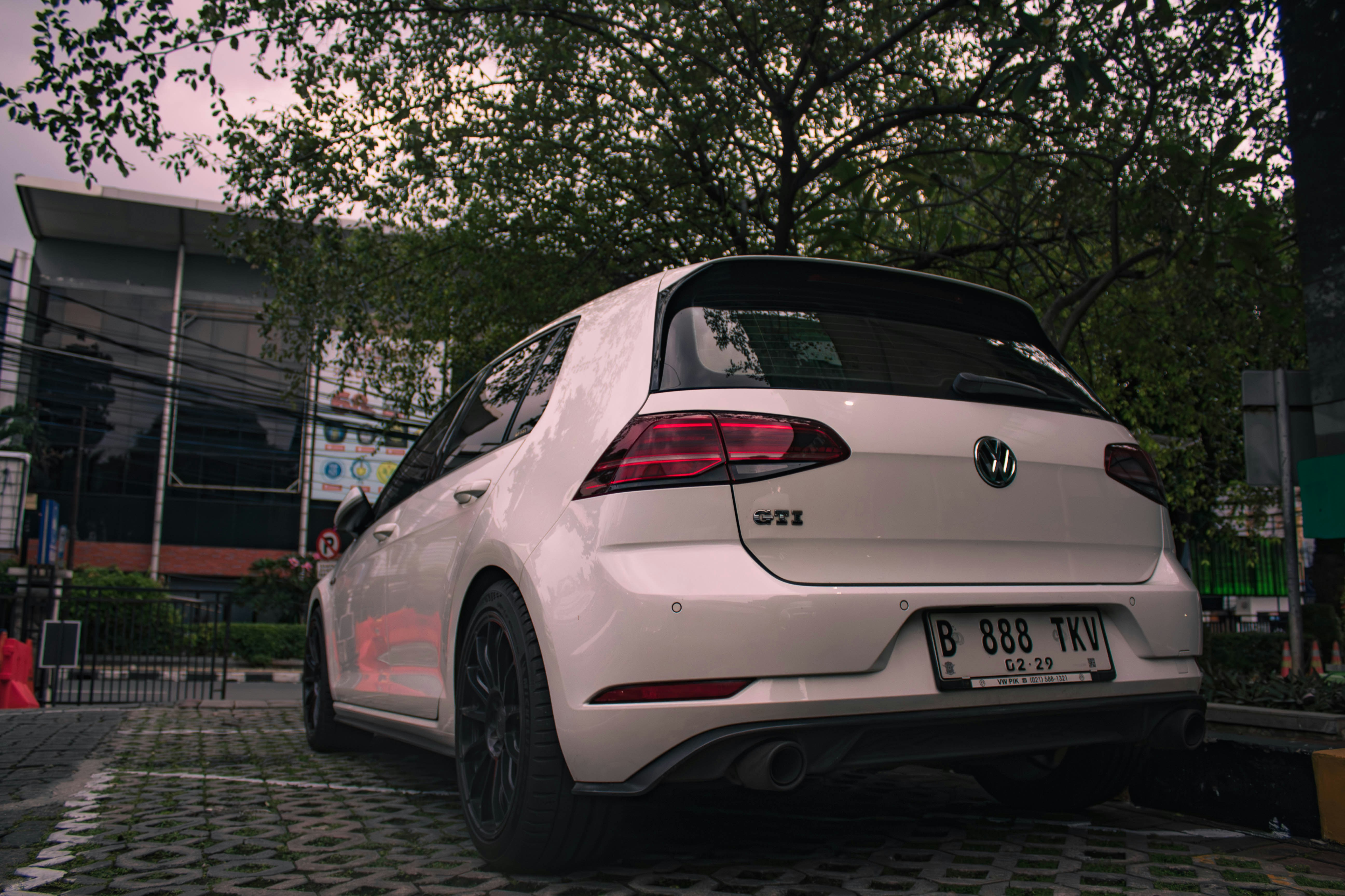 Twilight Rearview: A white hatchback anchoring a city parking scene