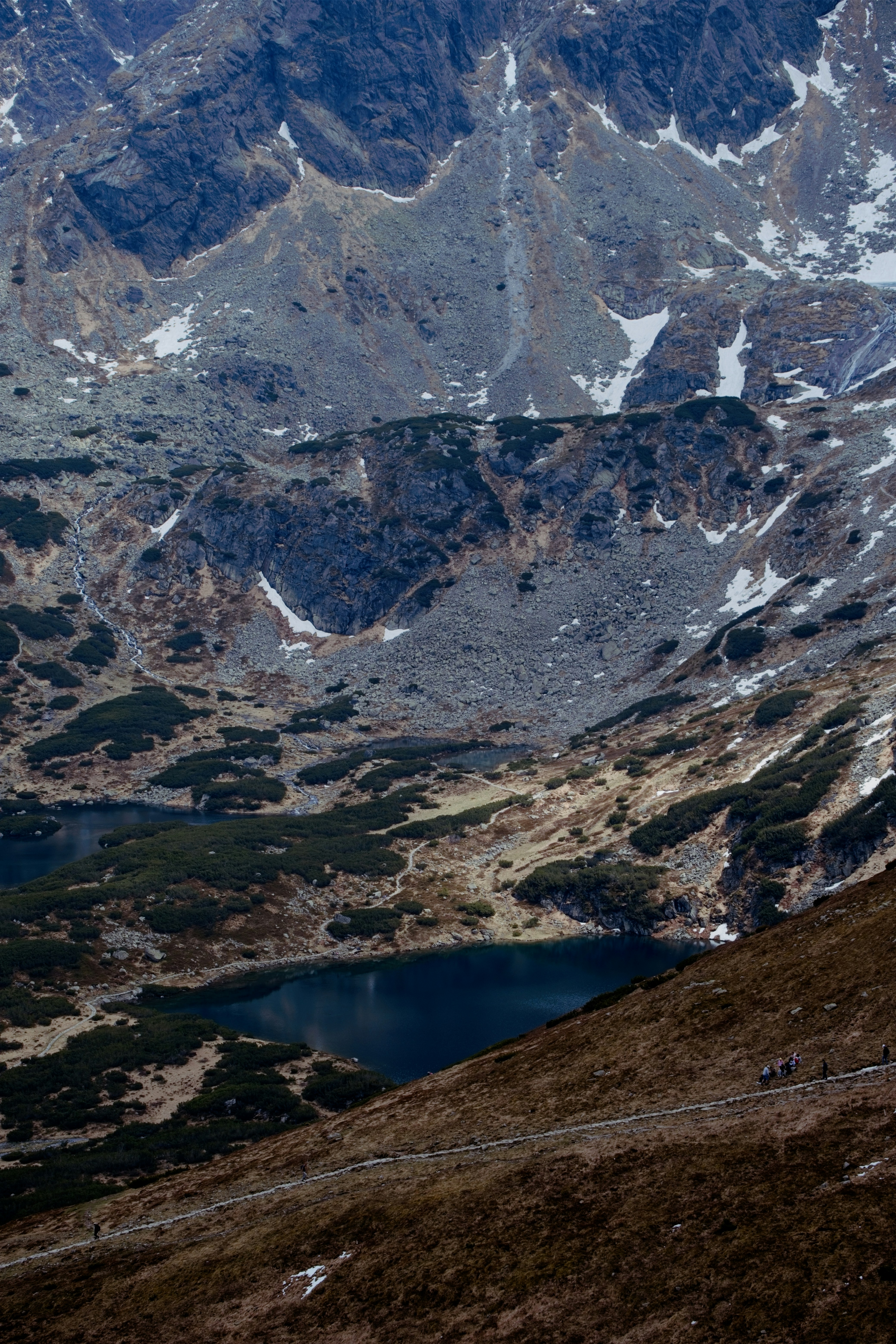 Mountains tower over a lake and path.