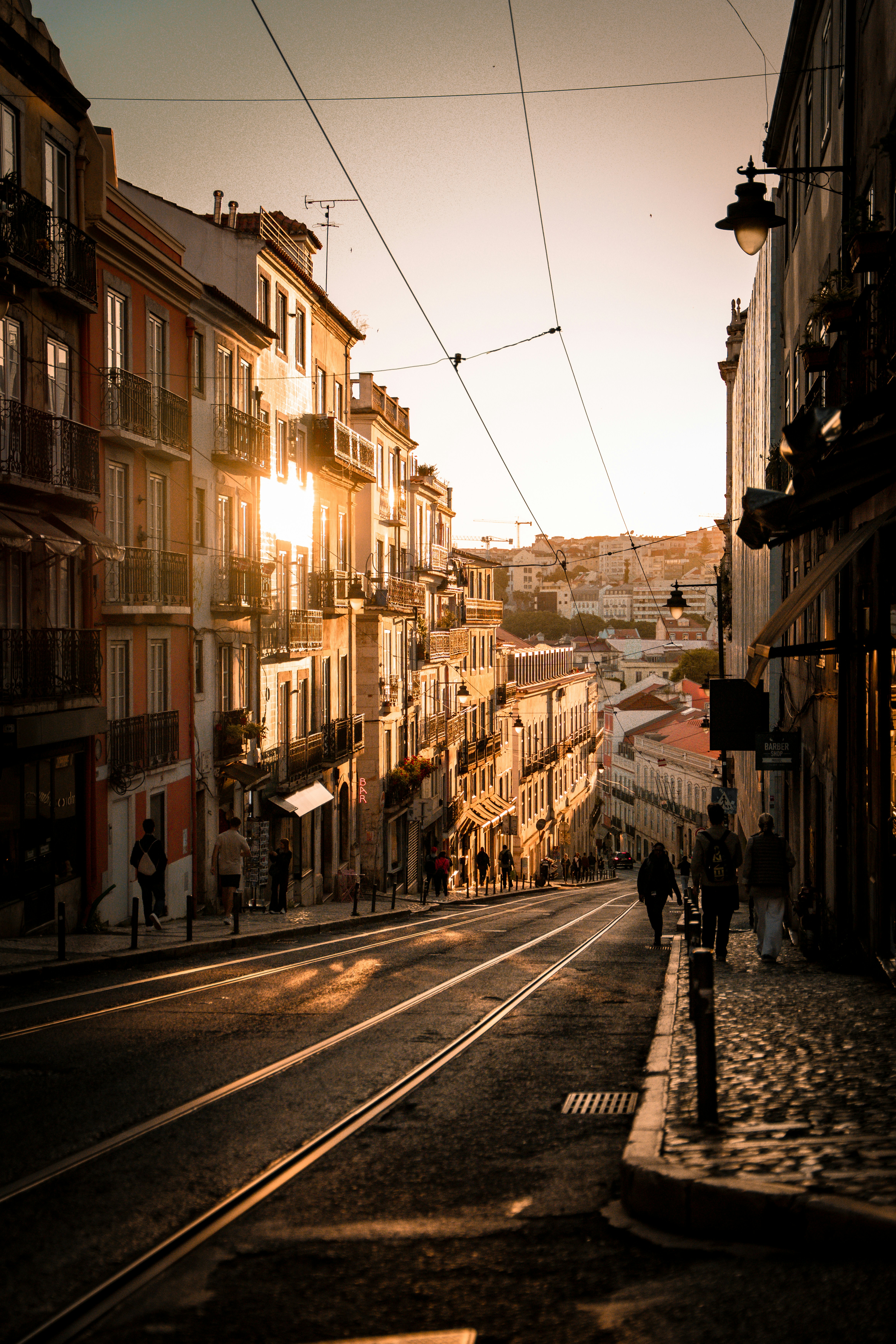 Sunlight reflecting off buildings along a cobblestone street in Lisbon, highlighting the charm of the city’s architecture during sunset.