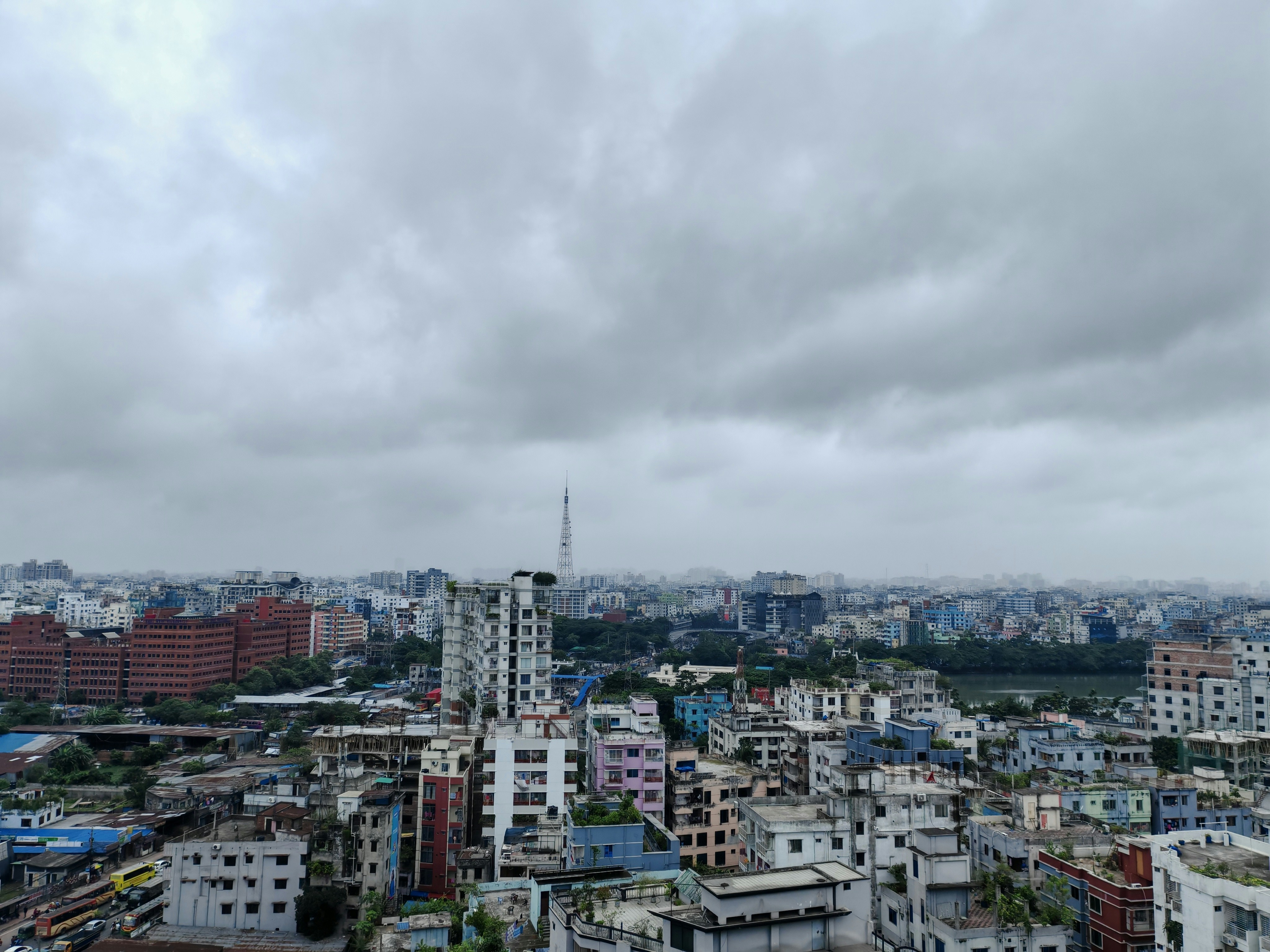 Expansive view of a densely populated cityscape with a mix of modern and older buildings under a cloudy sky. The iconic tower stands prominently in the background.