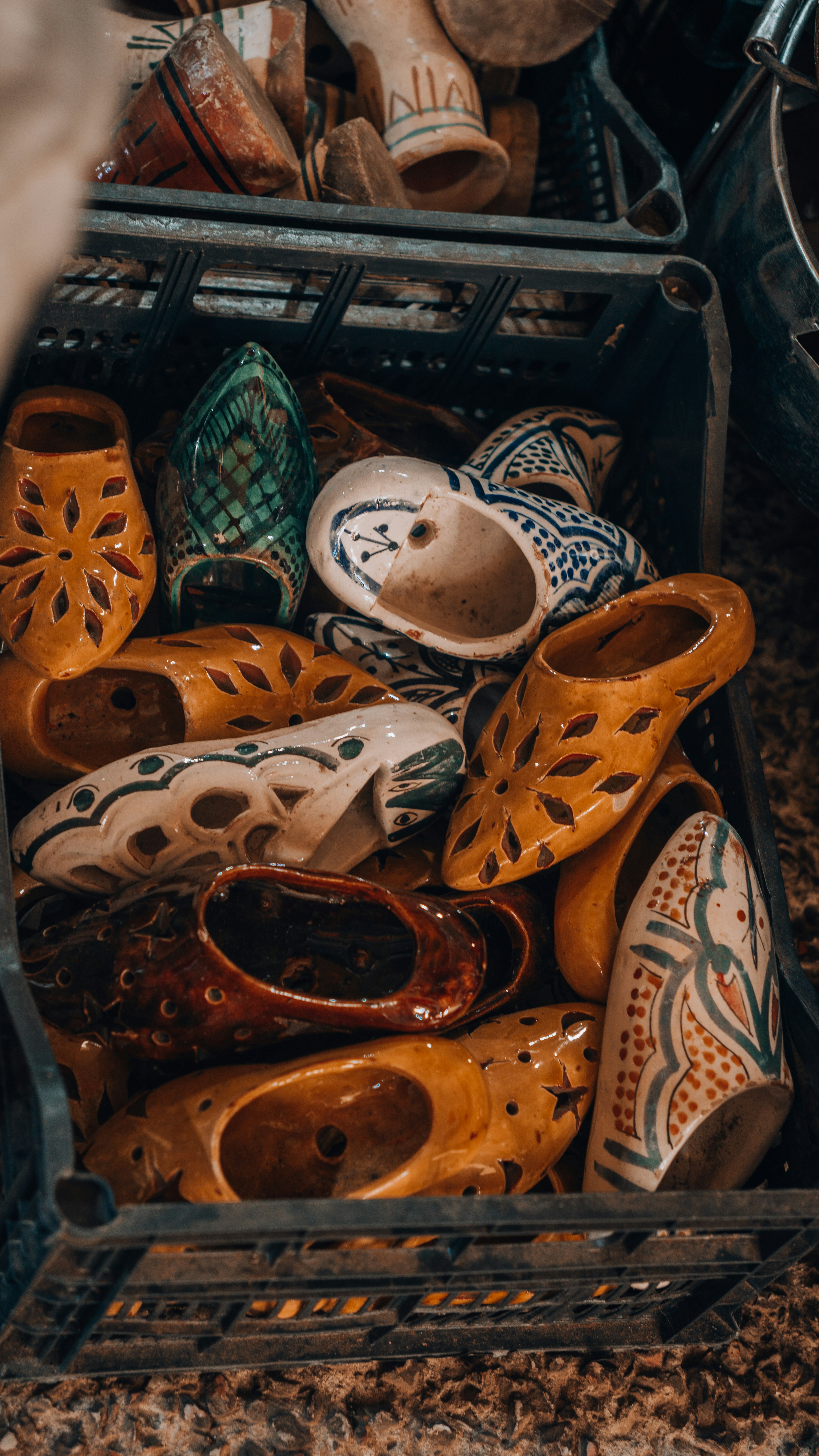 Handmade ceramic shoes in a plastic bin.