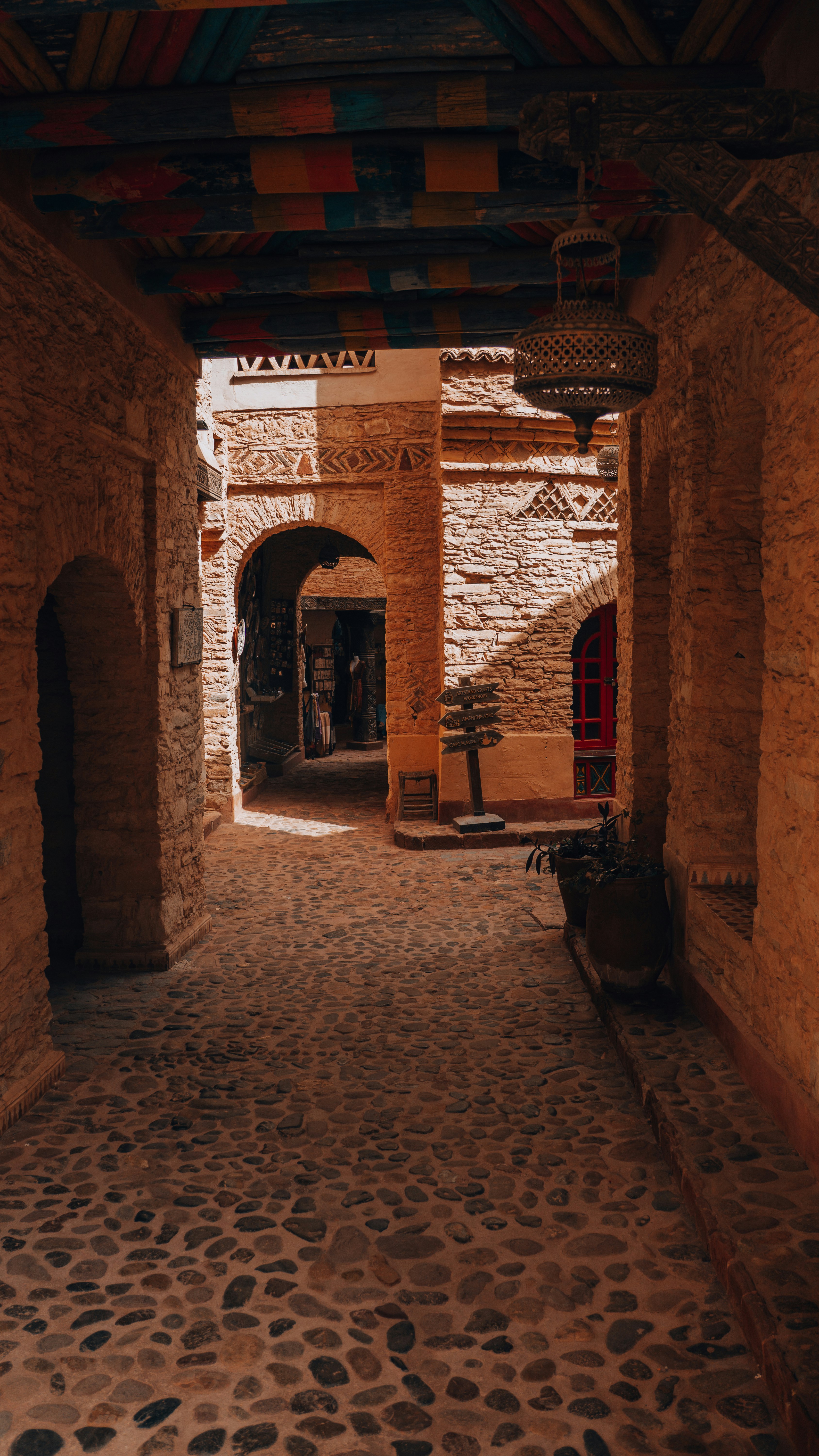 A narrow, cobbled alleyway in a sunny, warm setting.