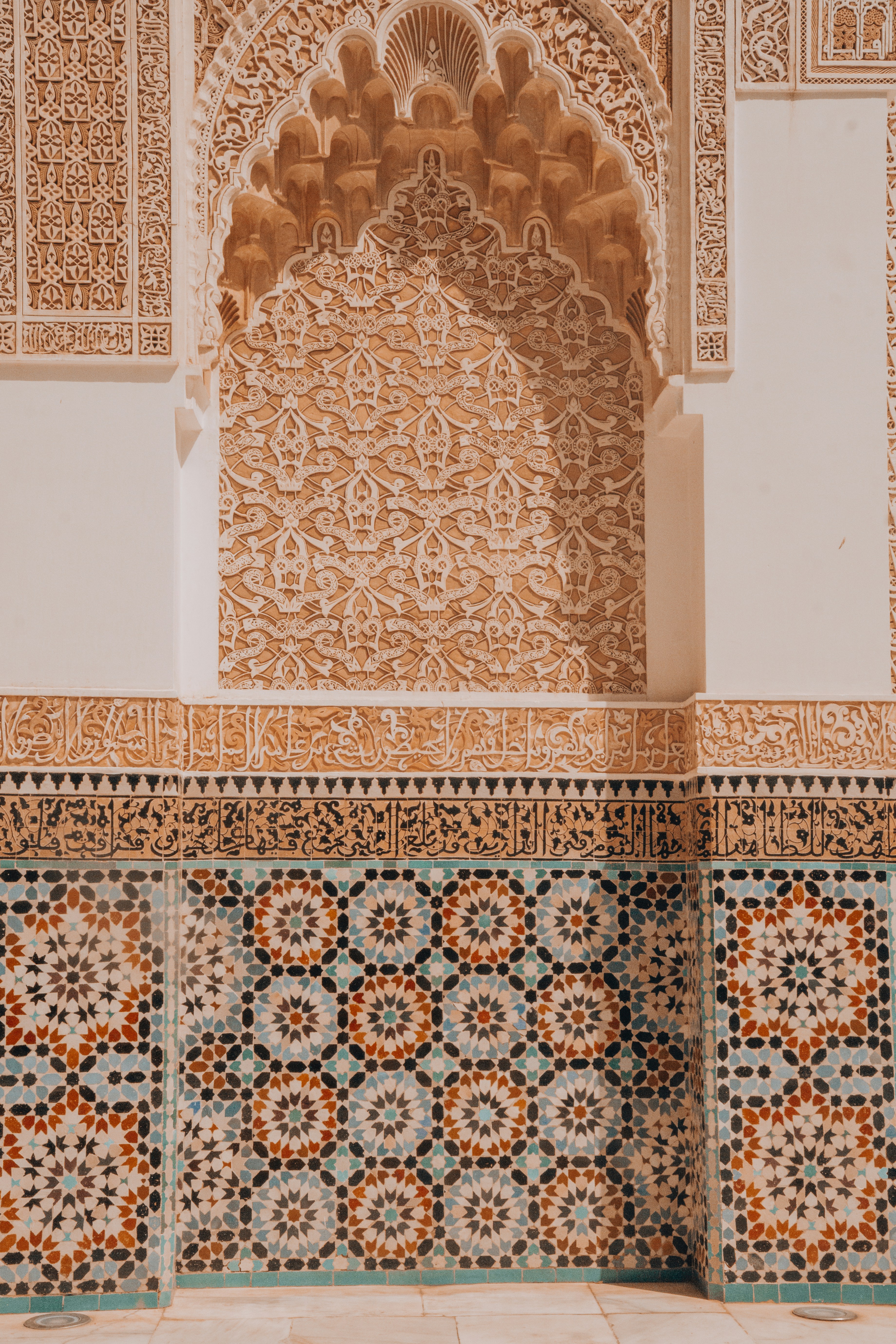 Detailed plasterwork and colorful tile patterns adorn a traditional Moroccan wall, showcasing the artistry of local craftsmanship.
