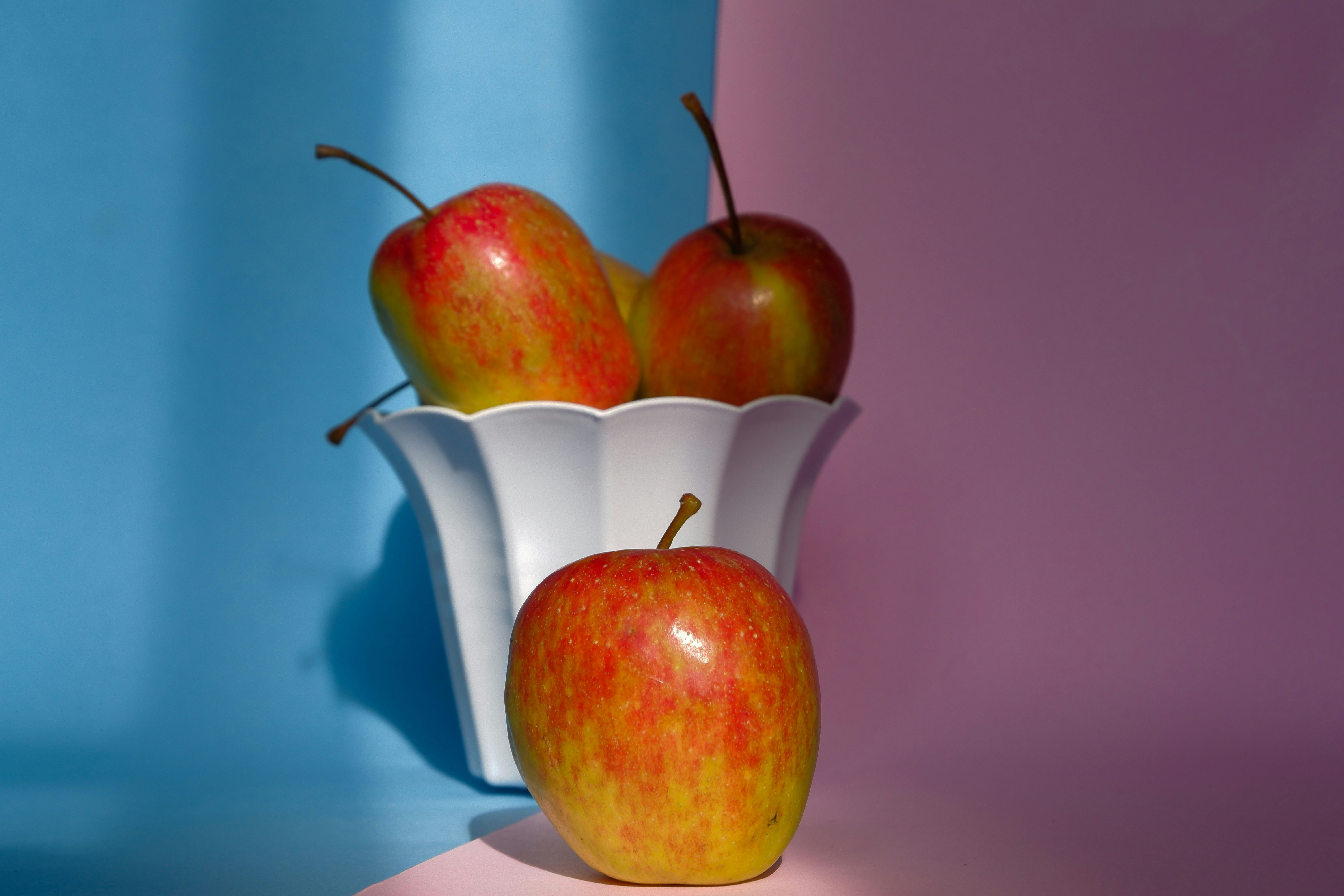 Photo of an apple in a container on a pink and blue background | Apples in a vase against blue and pink.