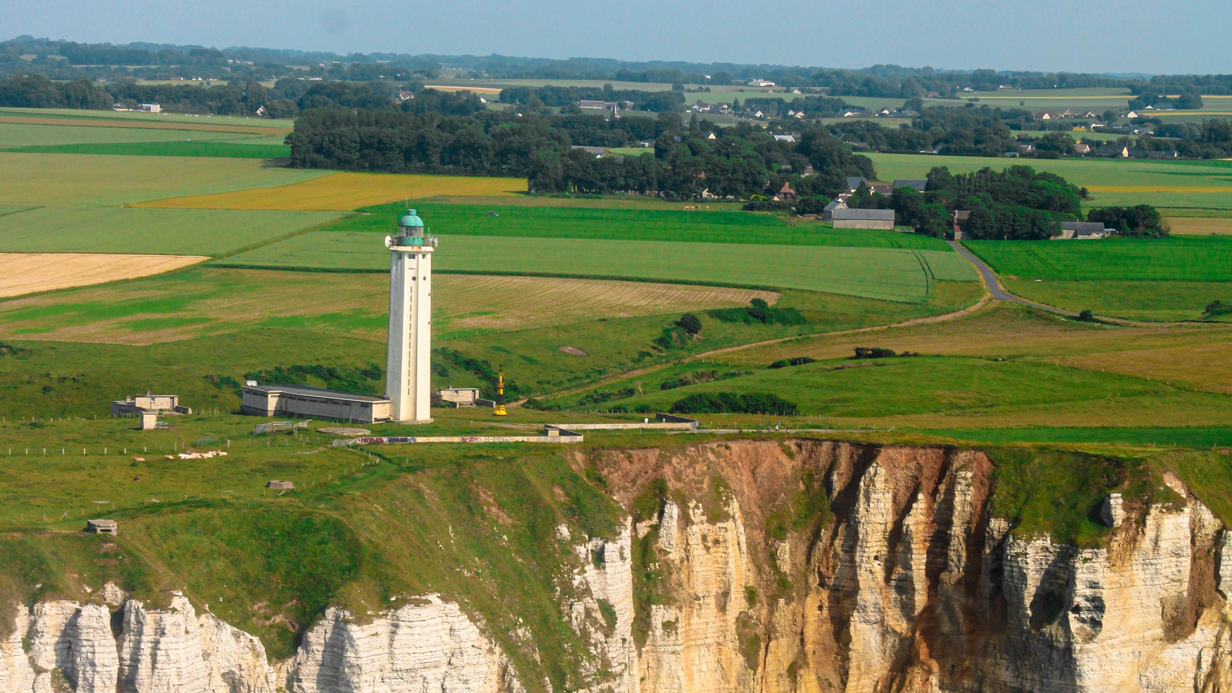 Cliffside Lighthouse Over a Sea of Green Fields