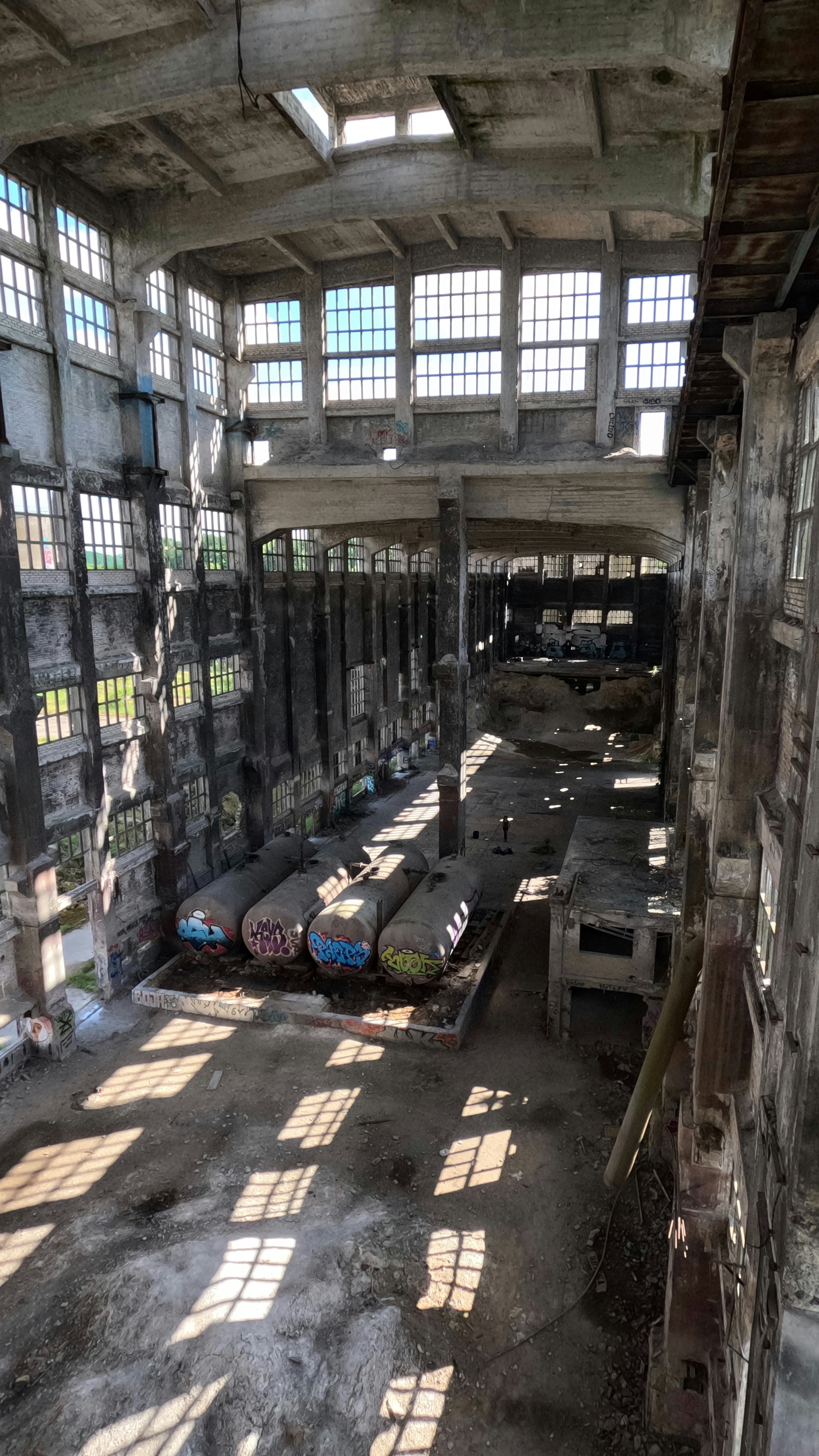 An abandoned industrial building with sunlight streams through.