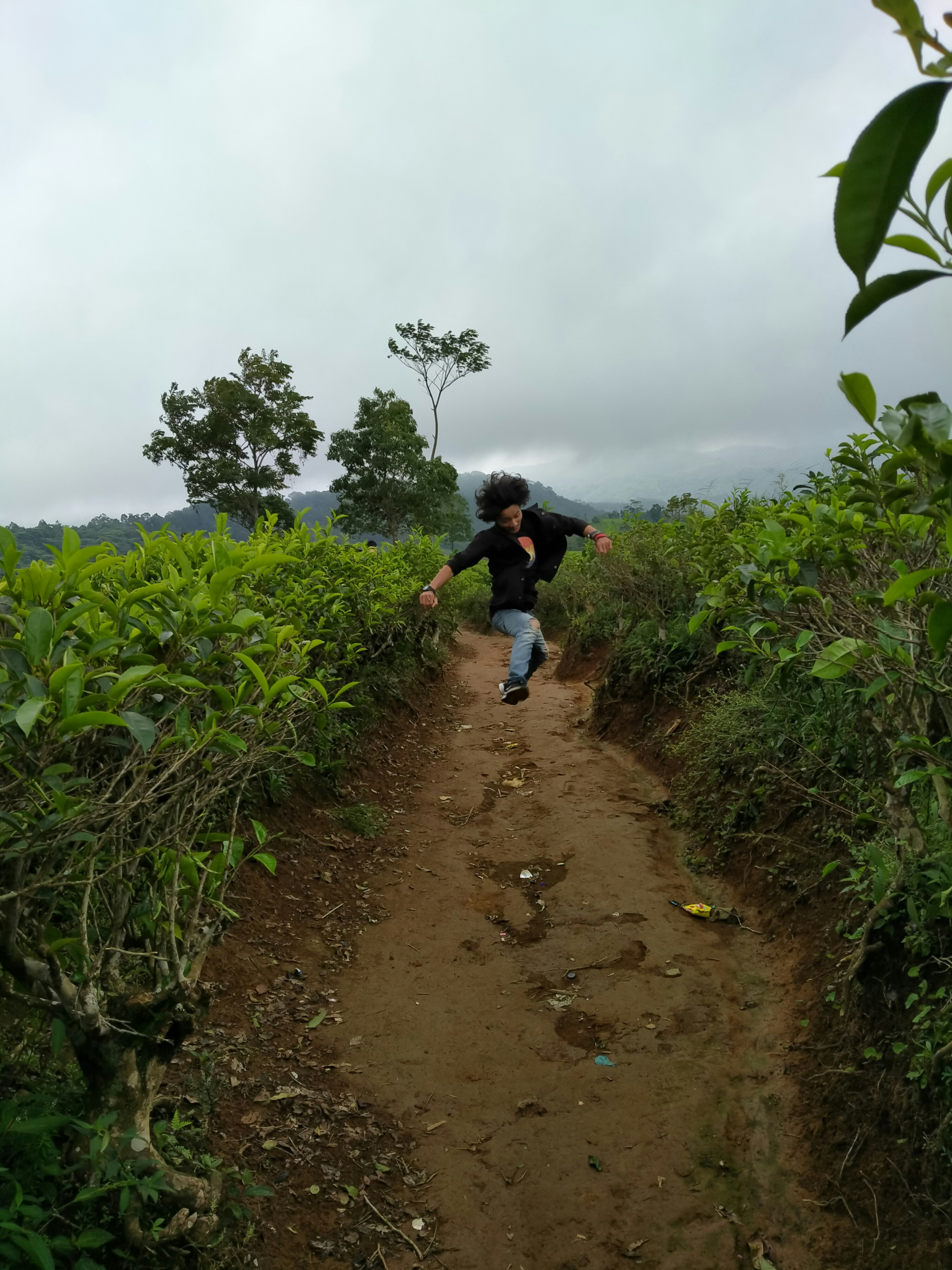 Man jumps with joy on a dirt path.