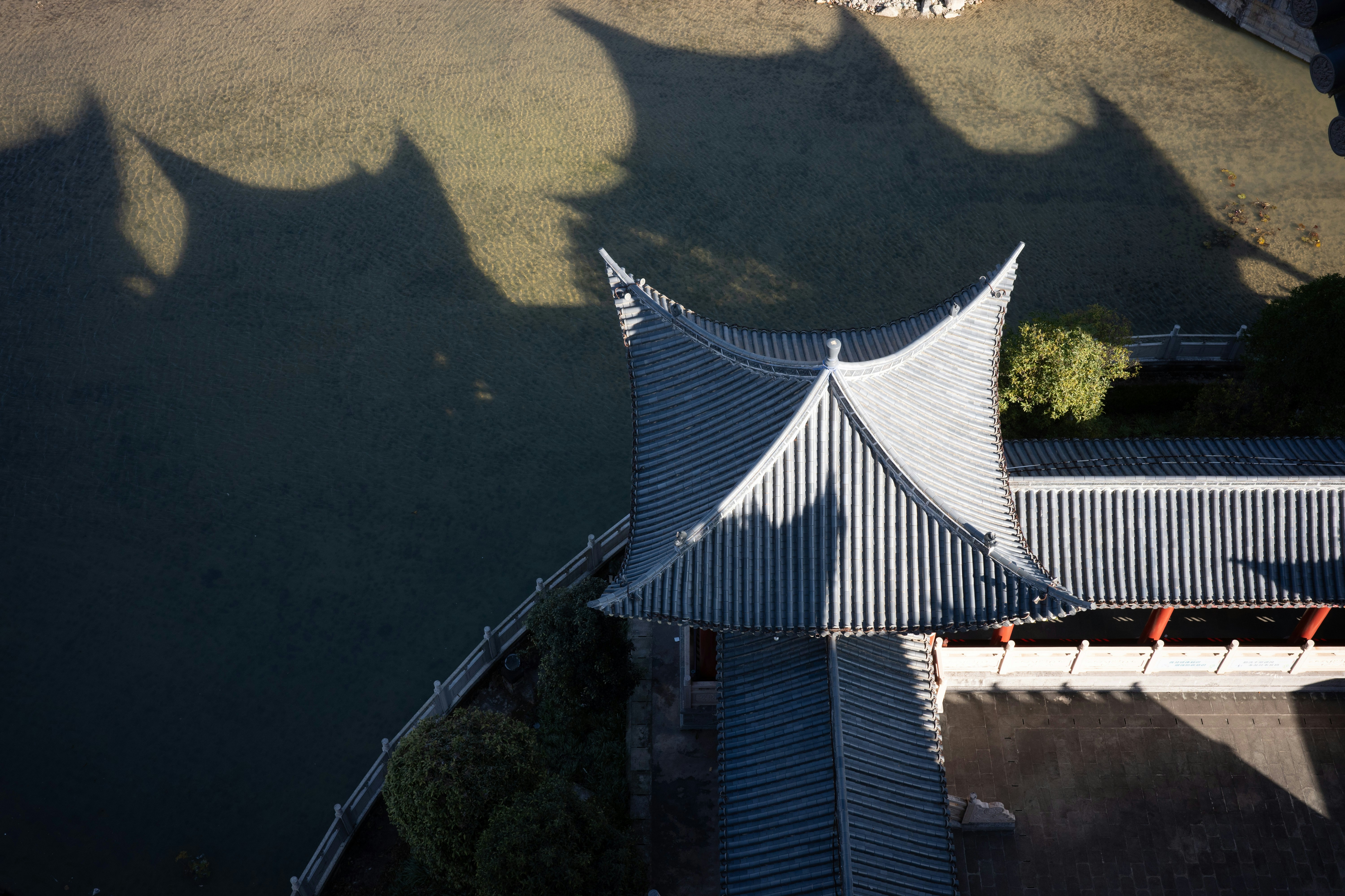A traditional building casts shadows on green ground.