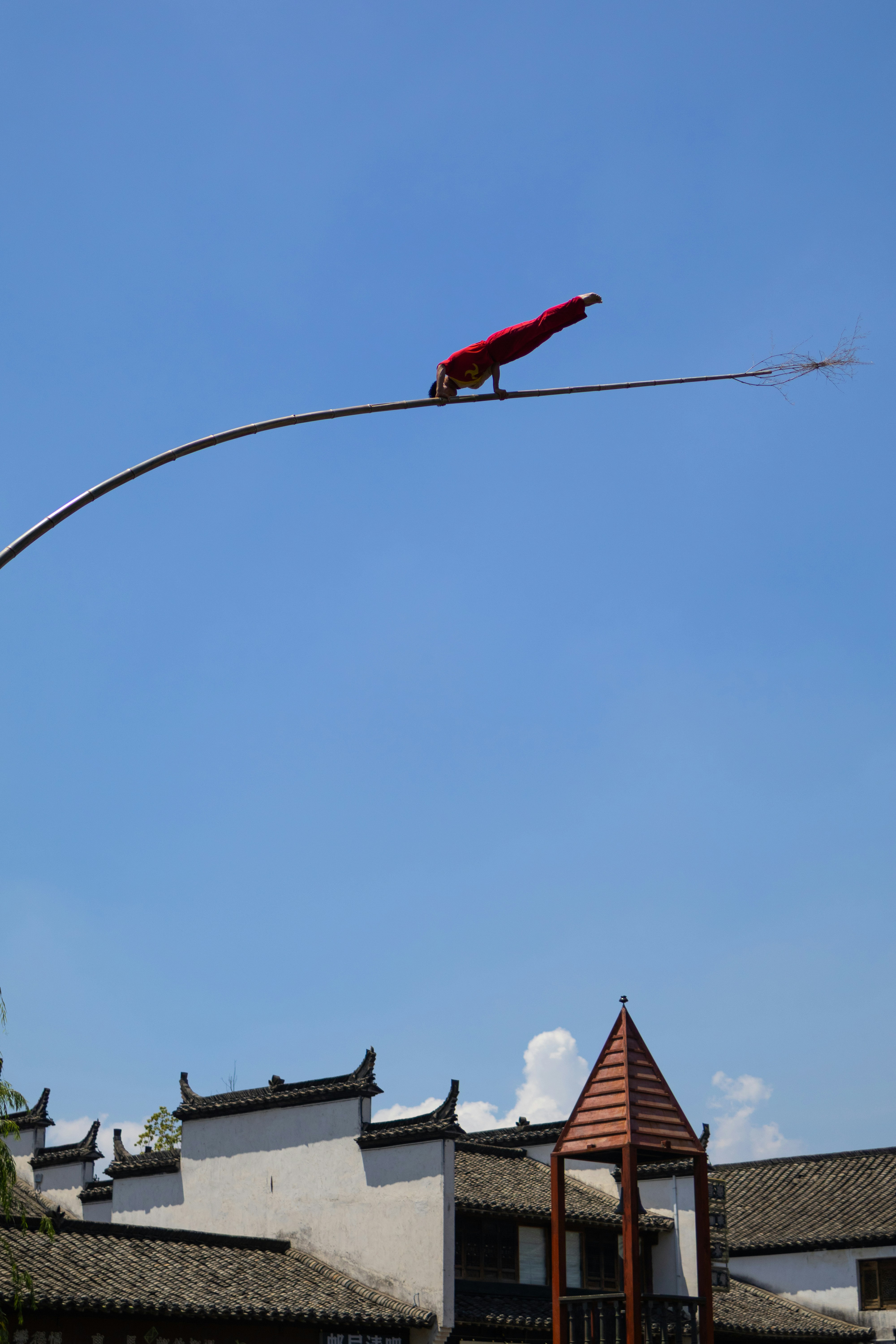 Acrobat performs balancing act on a flexible pole.