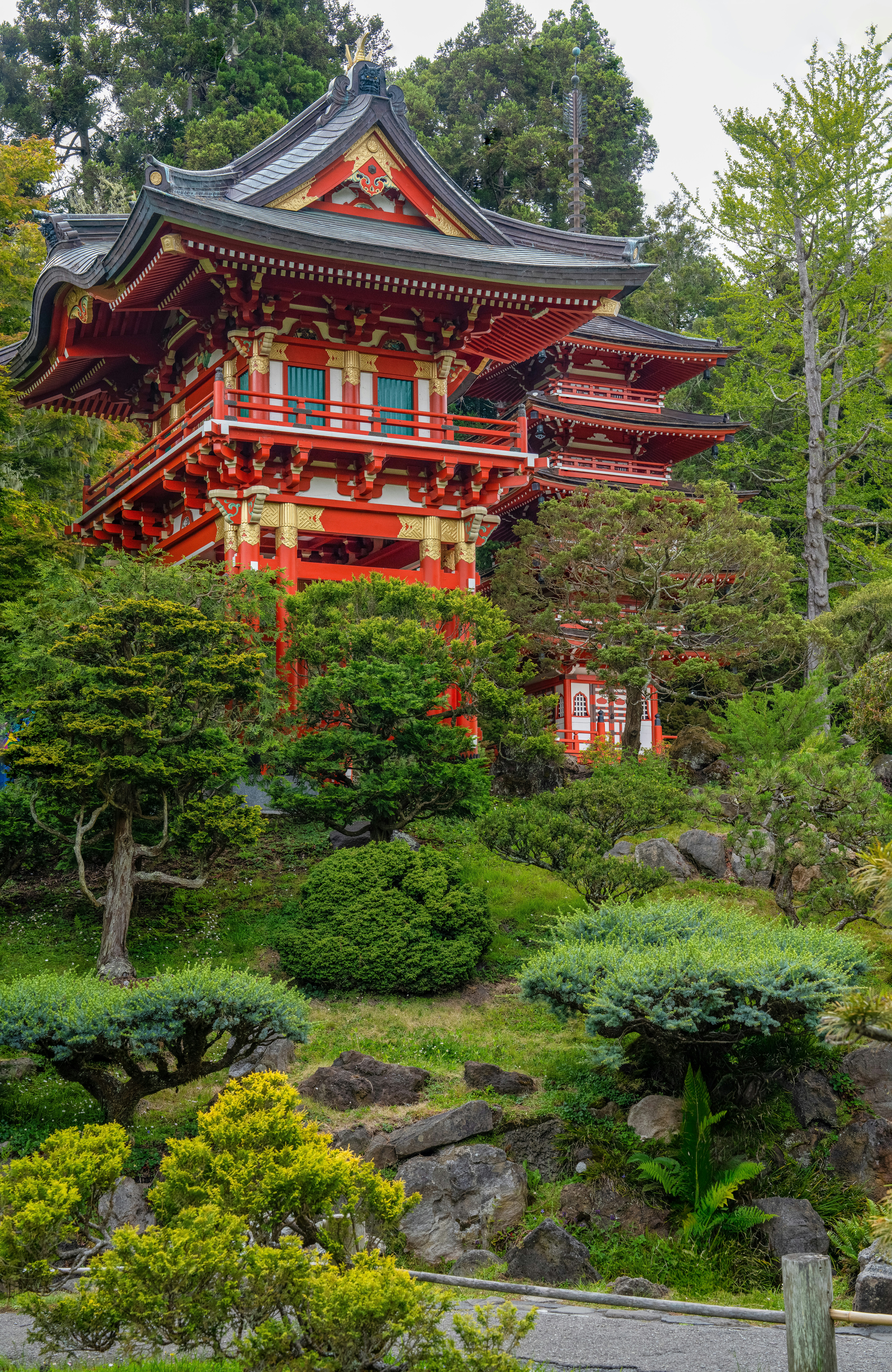 Vibrant red temple nestled among lush greenery, showcasing traditional Japanese architecture in a serene garden setting.