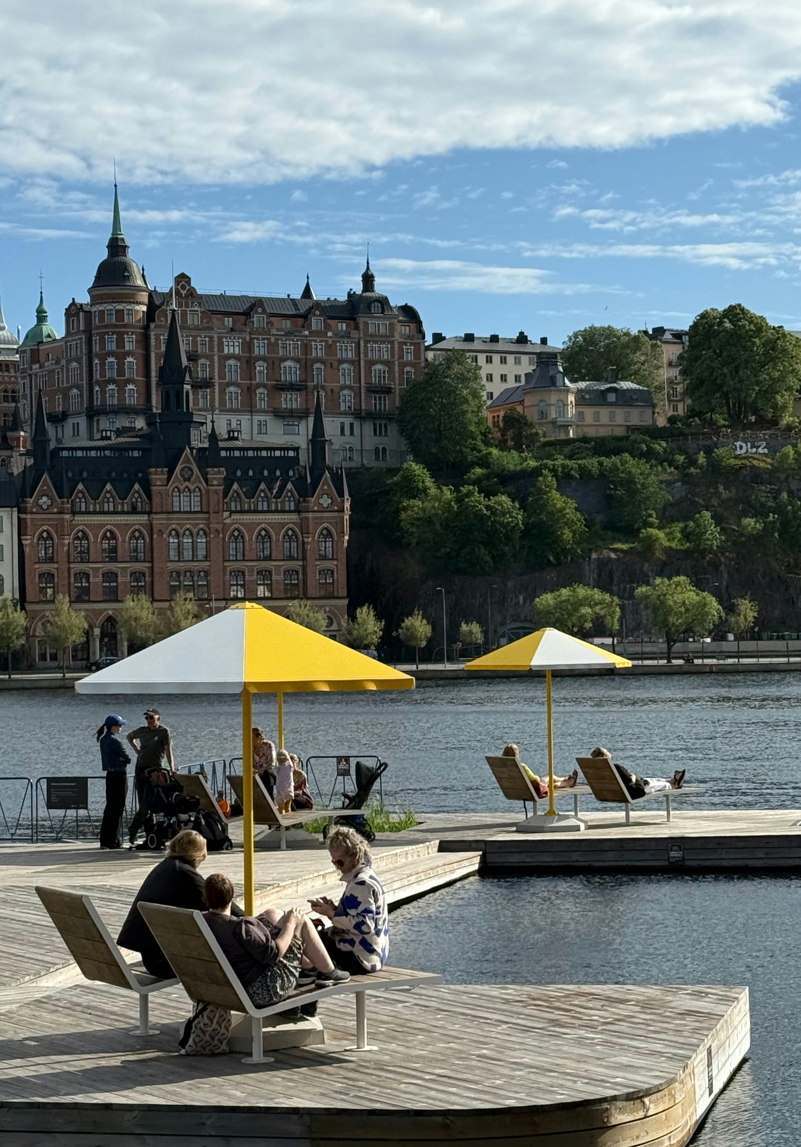 Sunlit riverside retreat with yellow parasols and historic cityscape