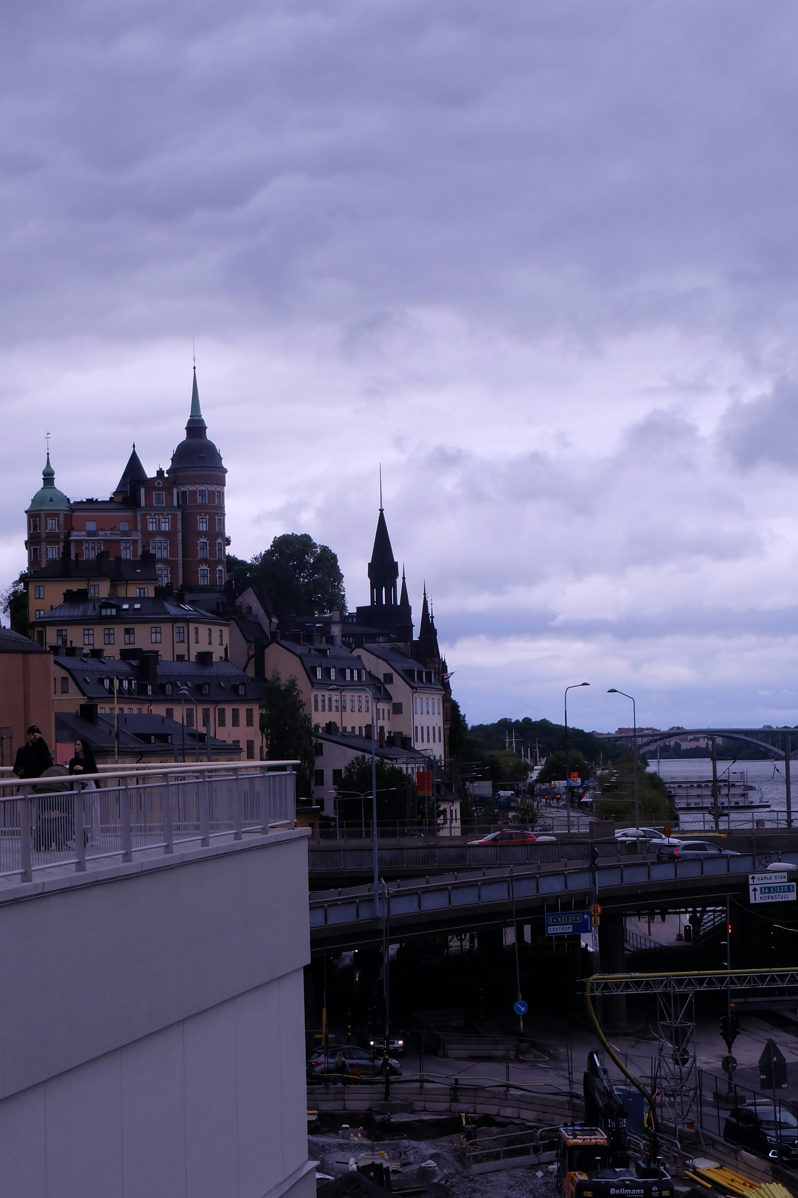 Historic buildings line the waterfront, framed by a dramatic sky, capturing the essence of urban life in a storied landscape.