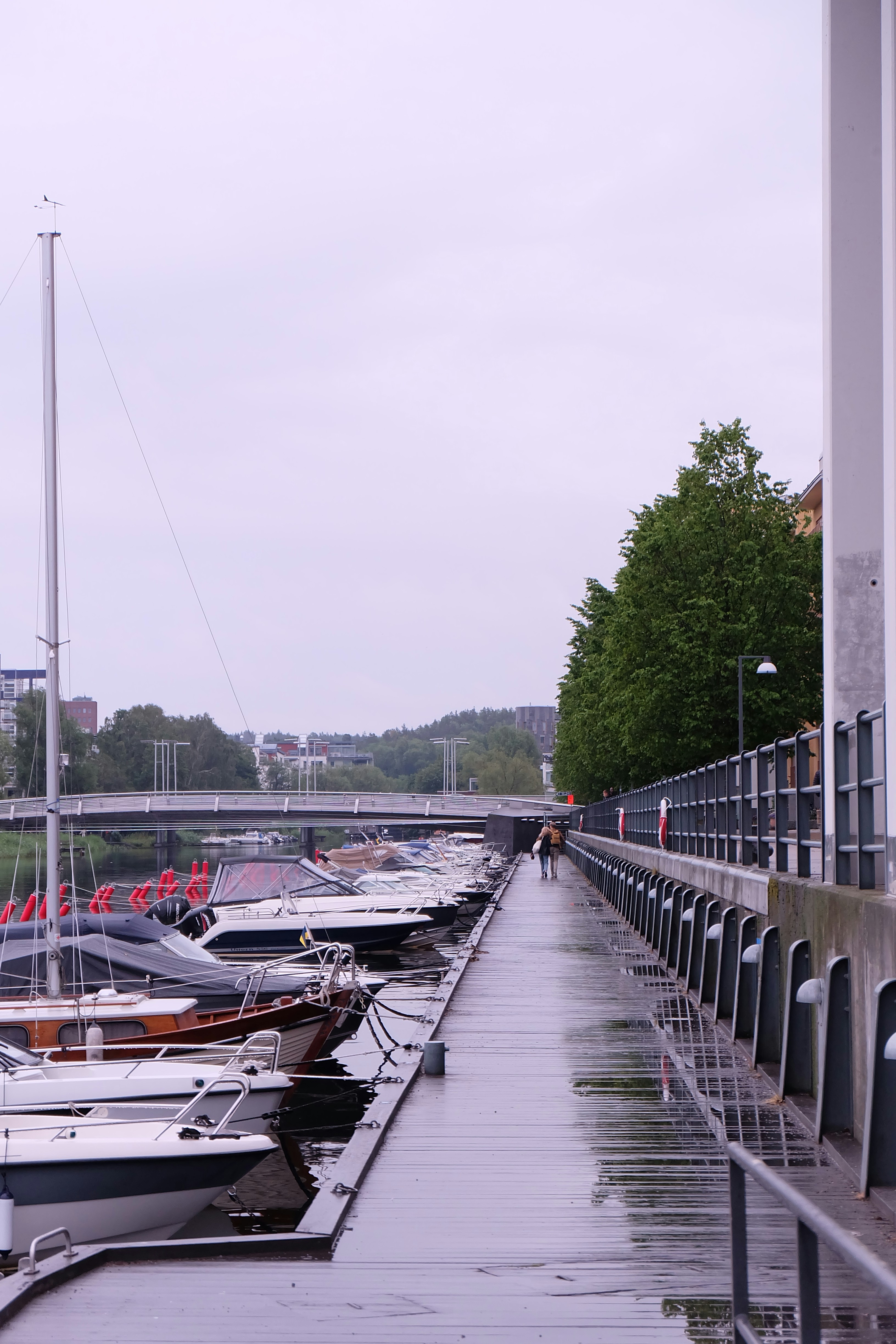 Boats are docked alongside a wet, wooden pier.