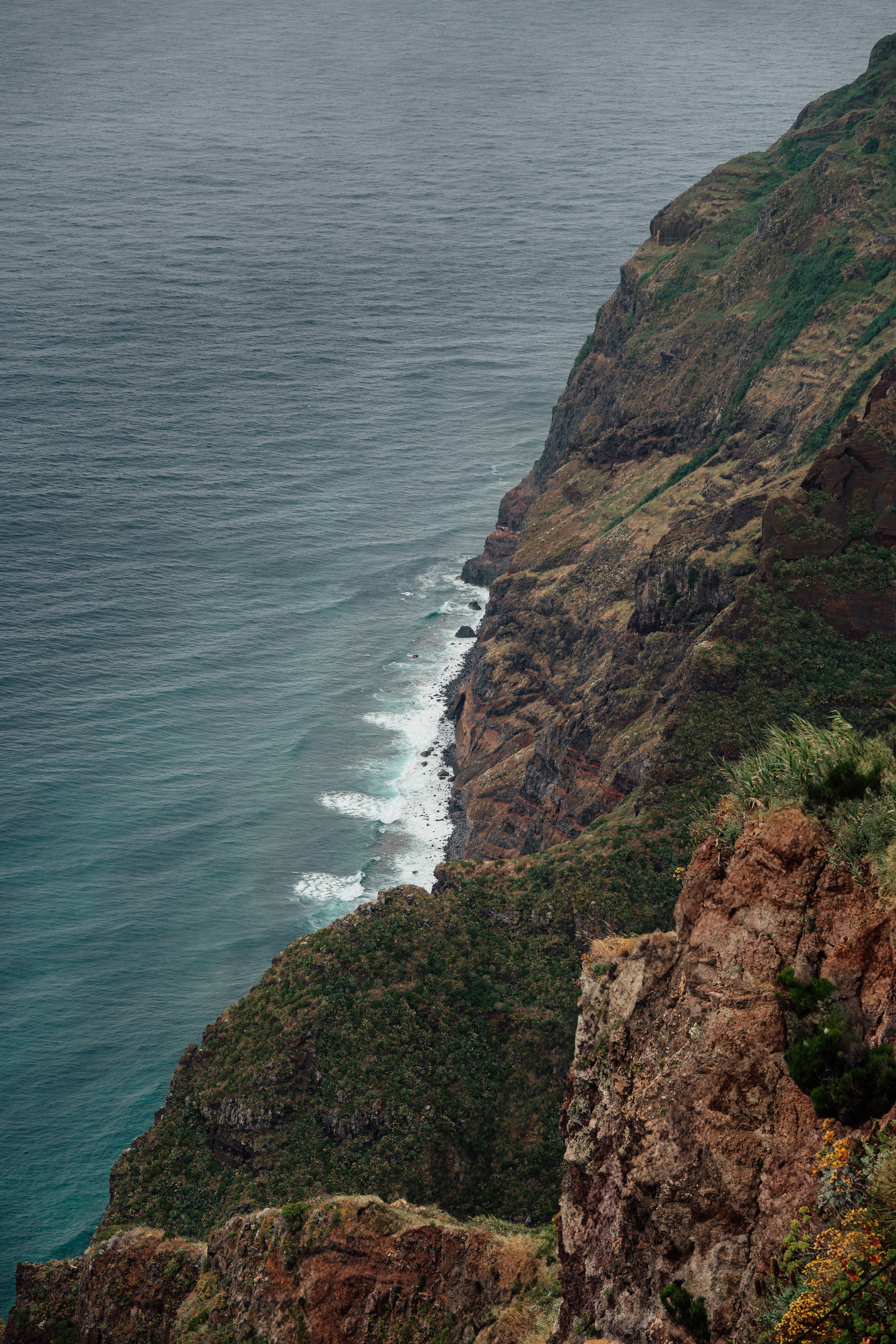 Rugged cliffs cascade into the ocean, showcasing the interplay of land and sea. The waves gently lap against the rocky shore, creating a serene coastal scene.