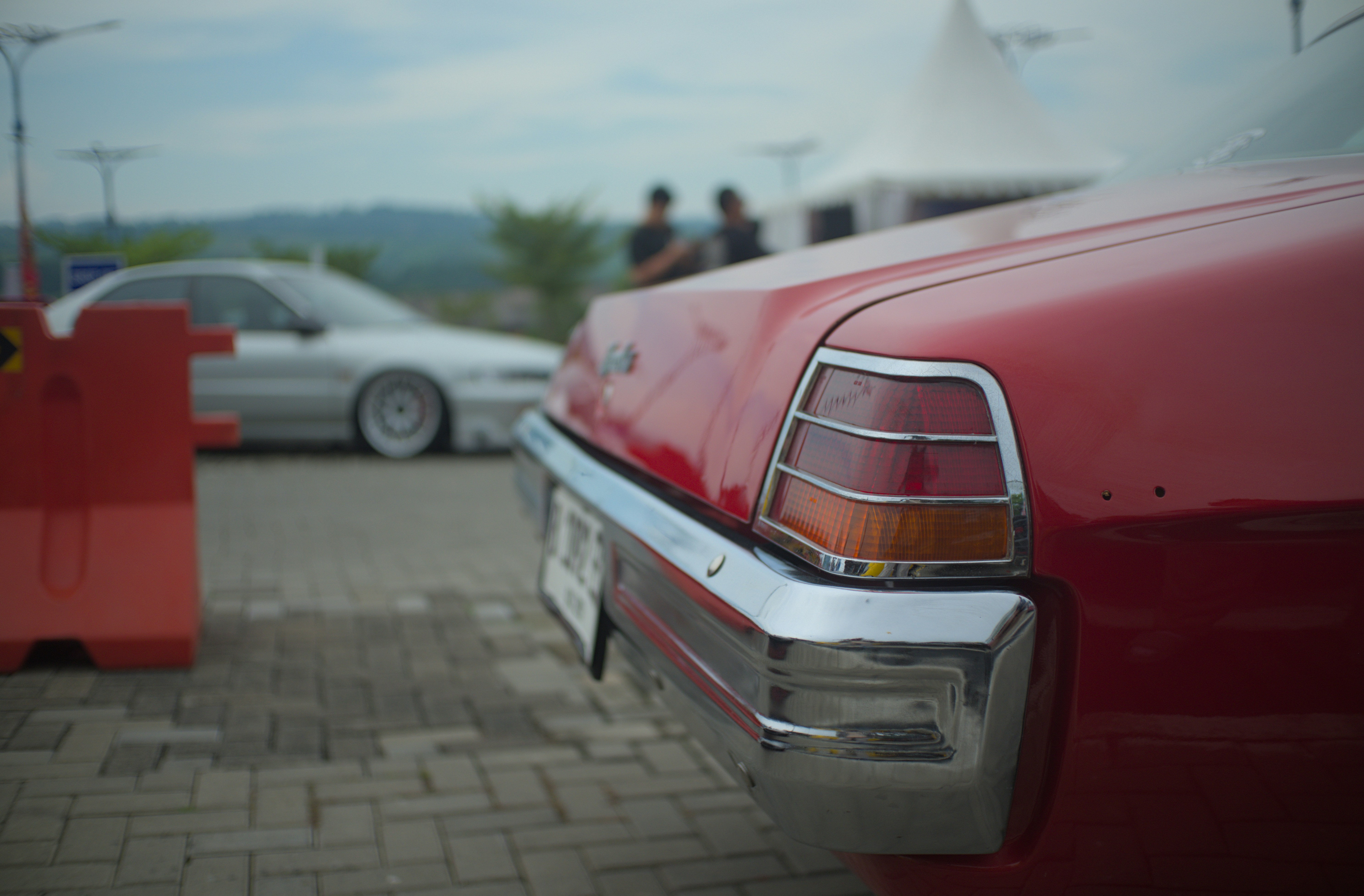 Red classic car's tail light is the main focus.