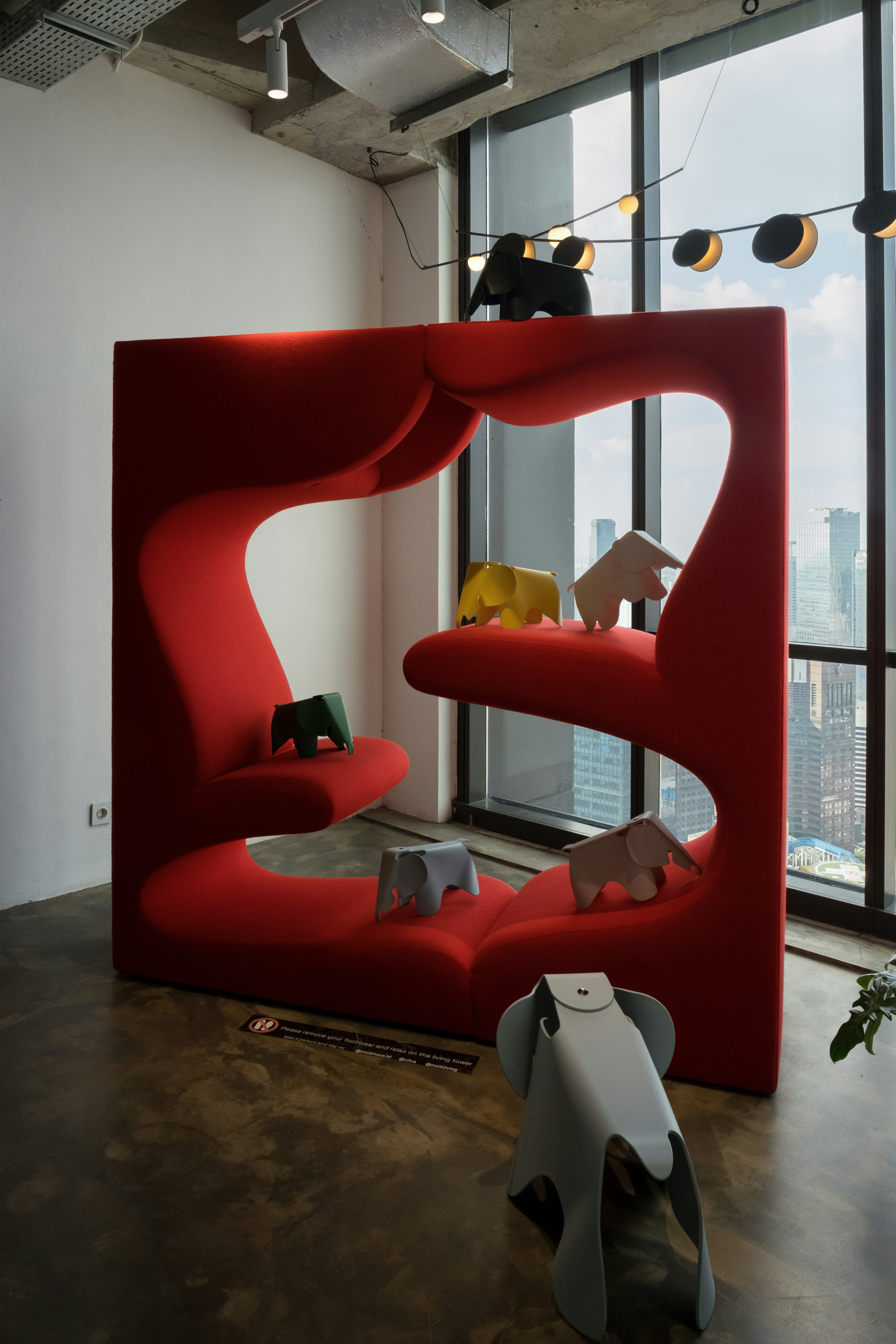 Red abstract sculpture with toy elephants.