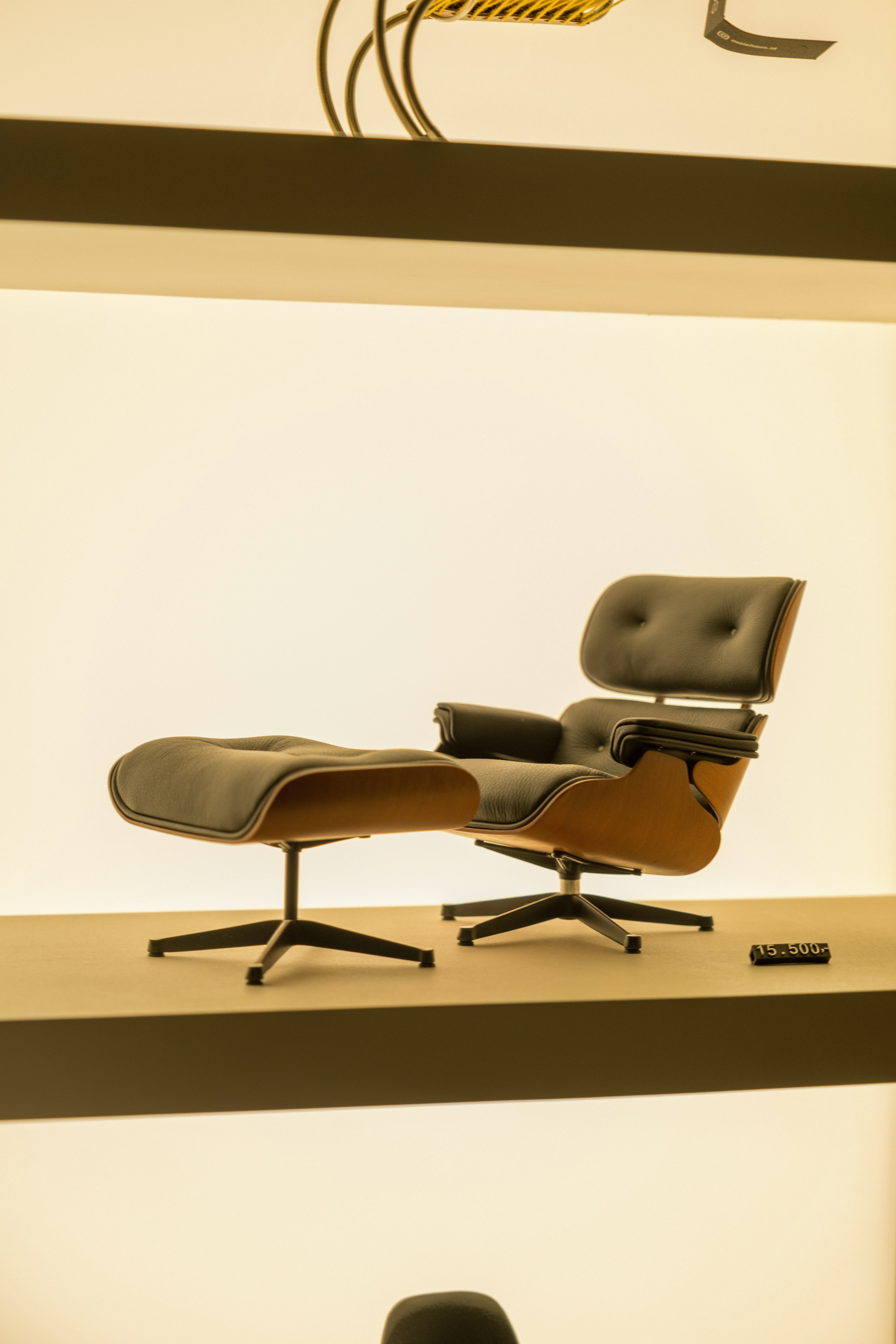 Iconic lounge chair and ottoman set against a soft, illuminated backdrop, showcasing their refined craftsmanship and modern aesthetic.