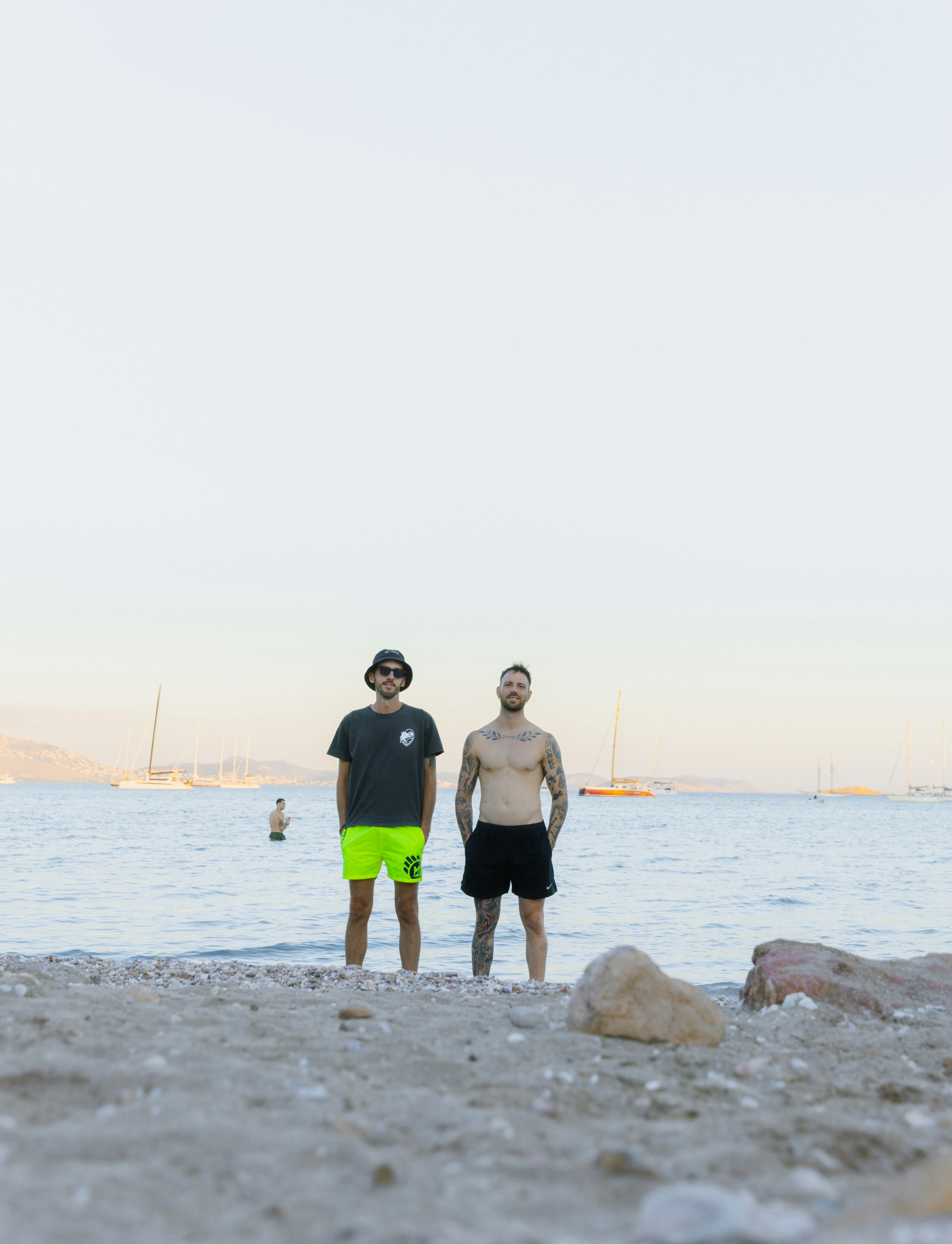 Two men stand at the edge of the ocean.