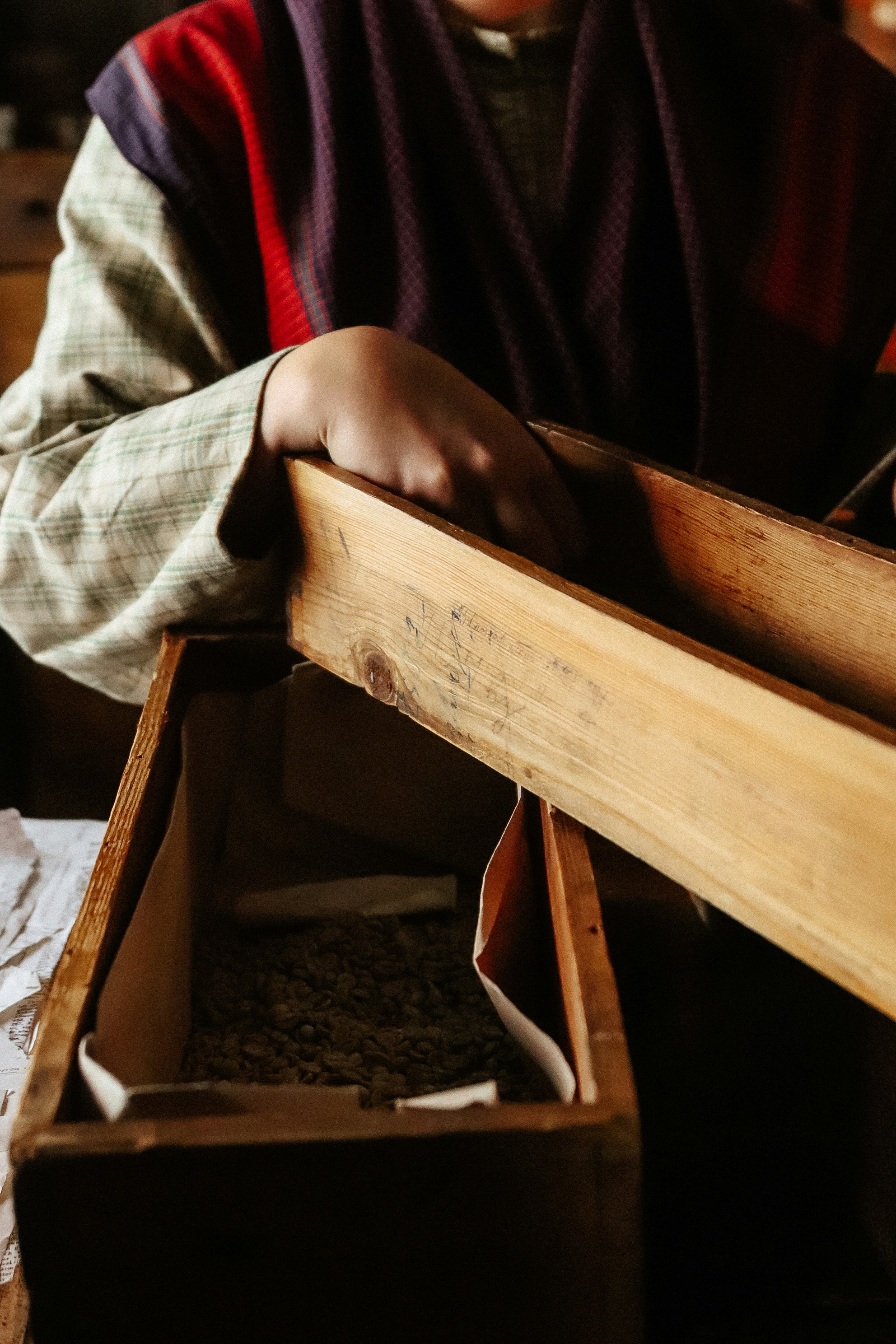 Beside the Box: A Hand Resting on Rustic Grain in Warm Light