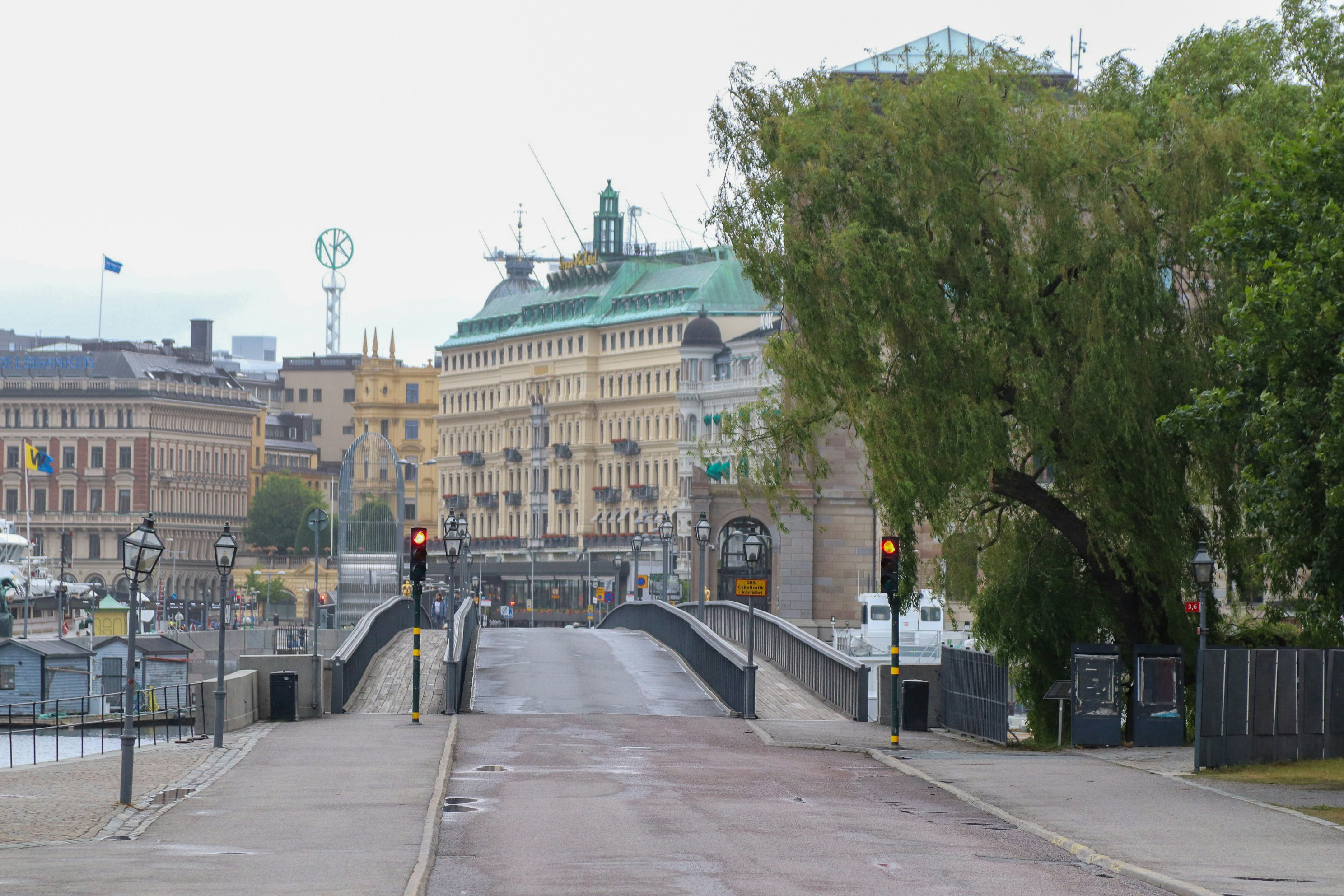 A bridge leads towards a city's buildings.
