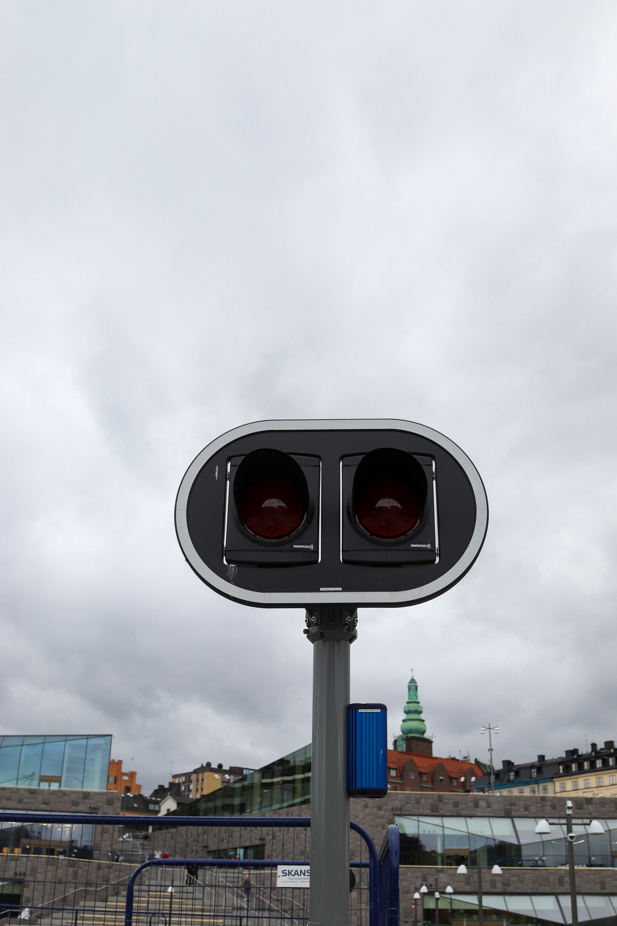 A pair of red lights against a cloudy sky.