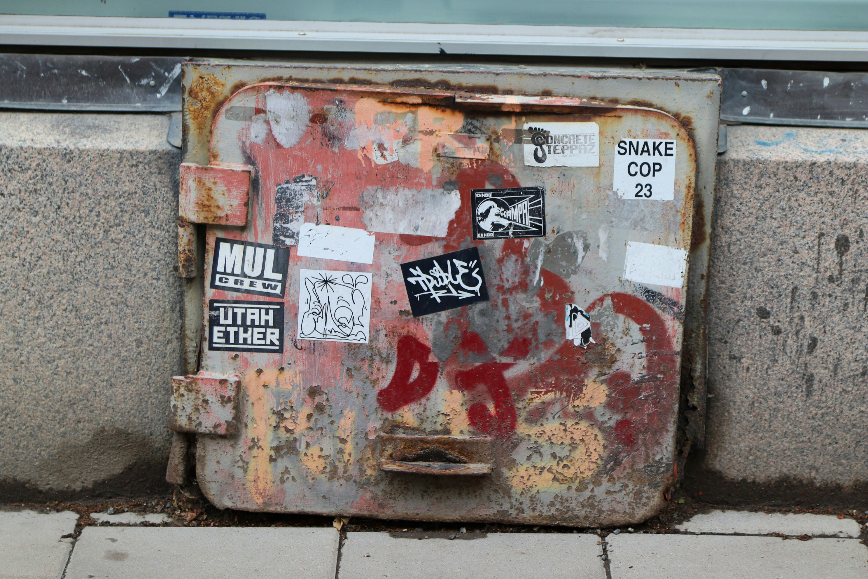 An old, weathered metal door is covered in stickers.