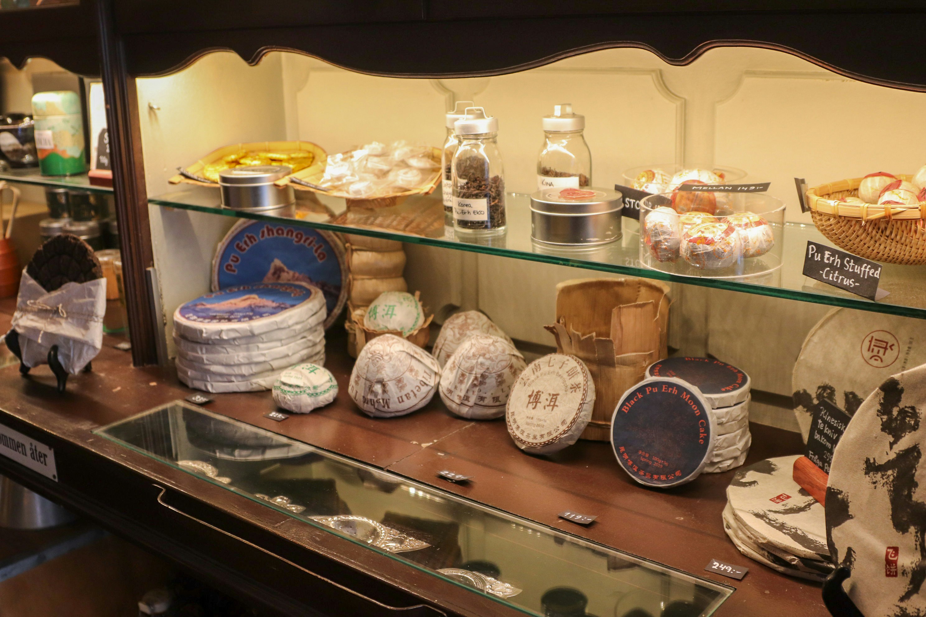 Display of various tea cakes and accessories in a wooden cabinet, showcasing the rich tradition of tea culture.