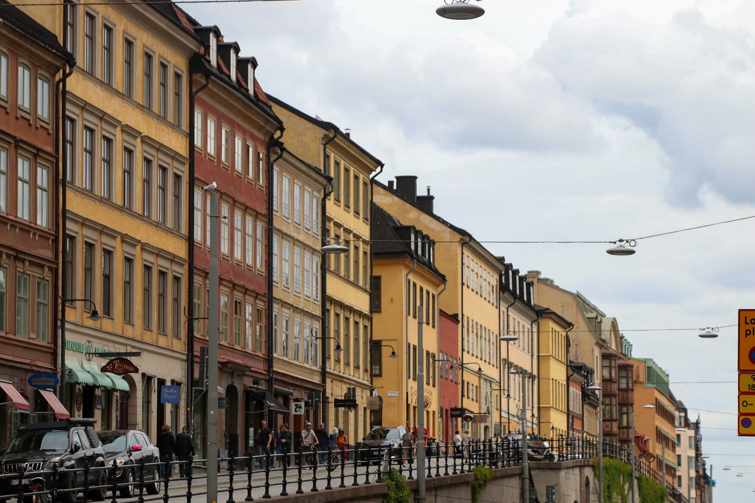 Vibrant row of historic buildings showcasing a palette of yellows and reds, with pedestrians enjoying the lively atmosphere along the waterfront street.