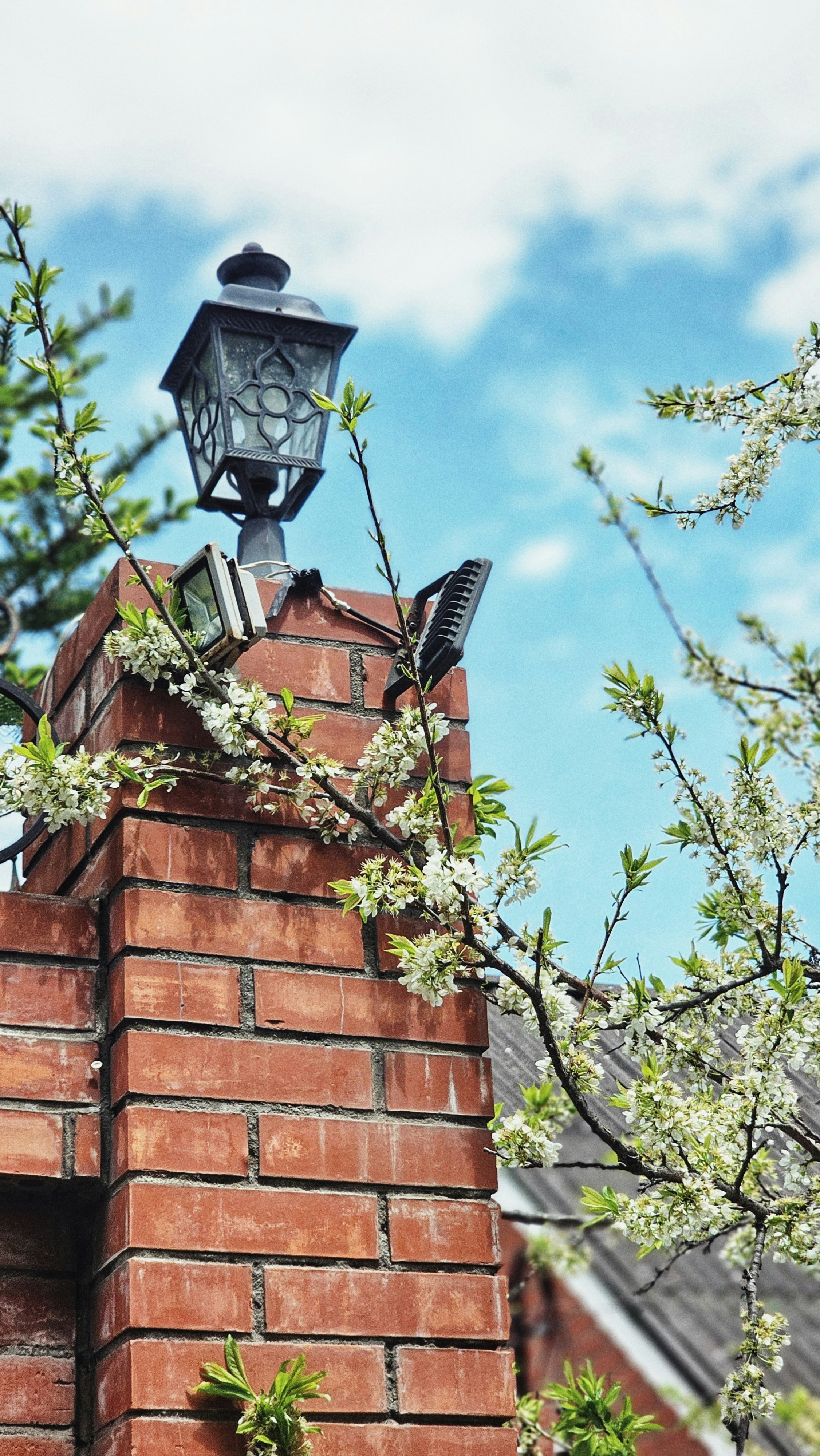 A brick pillar is adorned with blossoming branches.