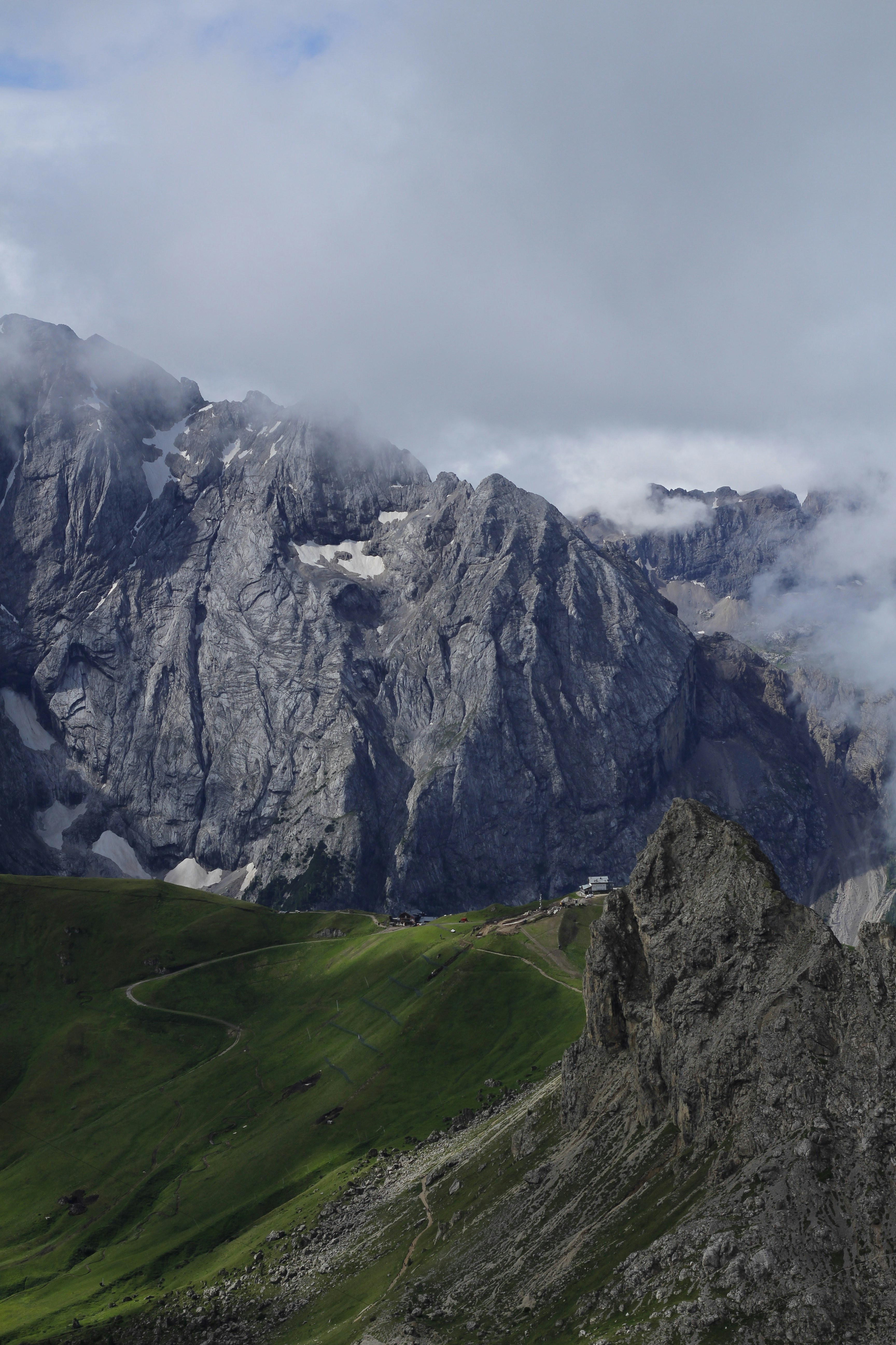 Majestic mountain range shrouded in mist, showcasing rugged cliffs and lush green valleys below.