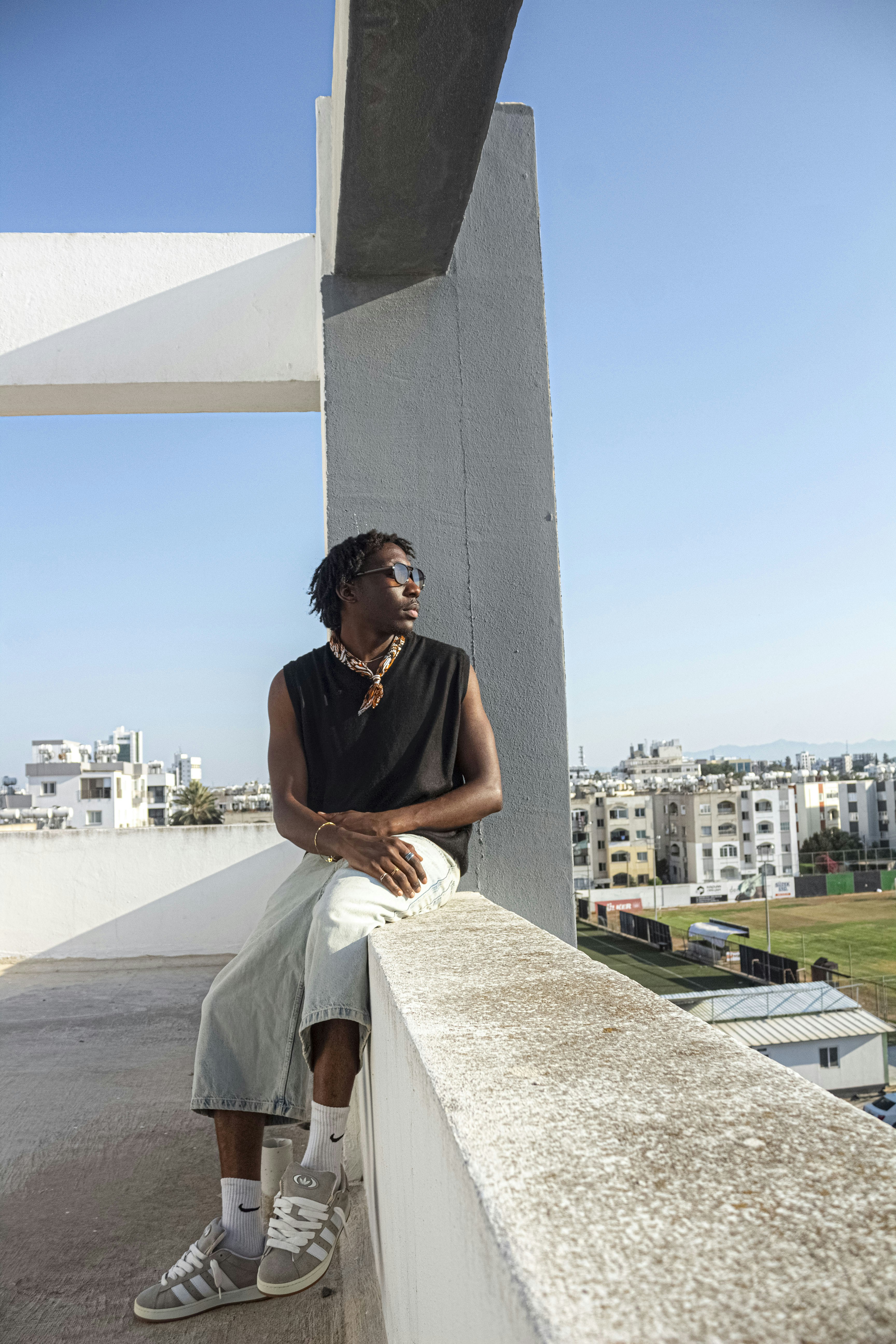 Man sits on rooftop ledge, looking away. photo – Free Human Image on ...