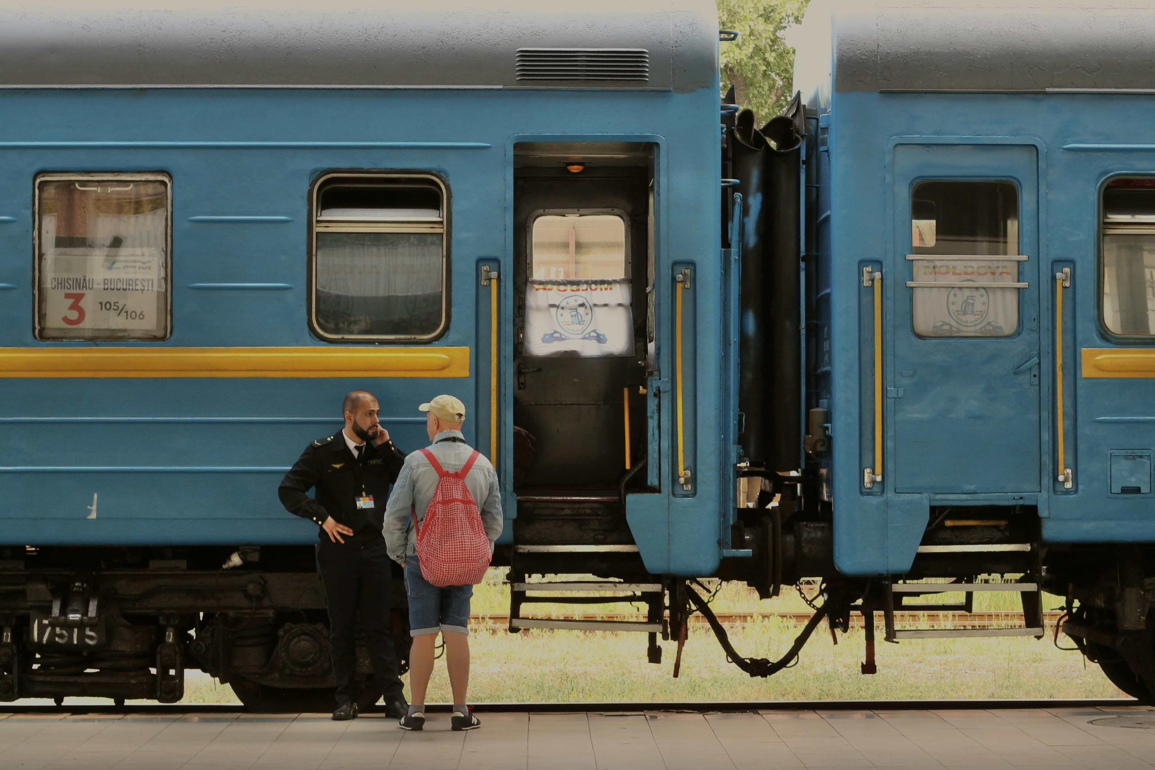 Image of a passenger talking to the train guard next to the Prietana (Friendship) sleeper train between Chisinau, Moldova and Bucharest, Romania. | A man talks with a train conductor.