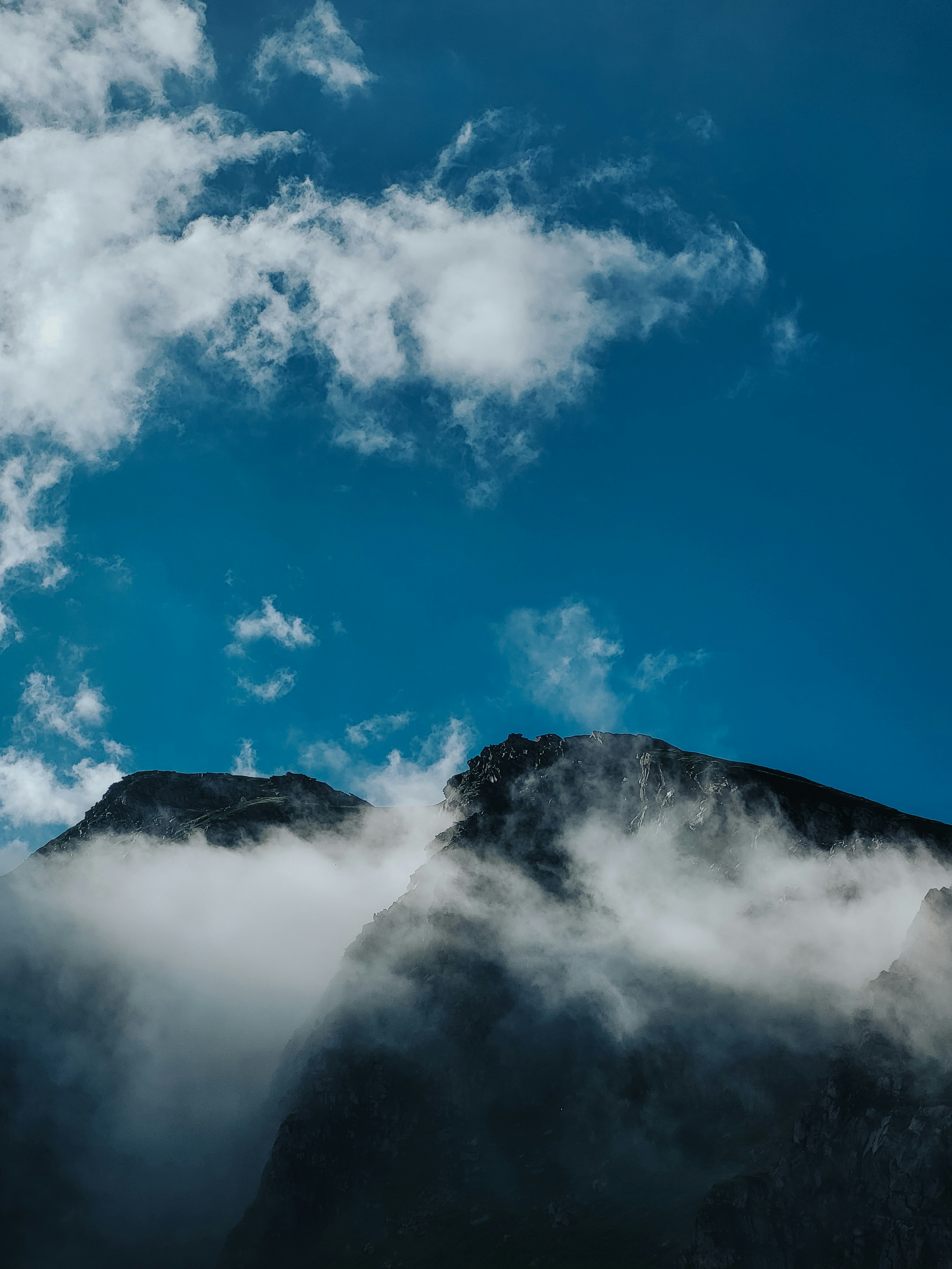 Mountains rise above the fog and clouds.