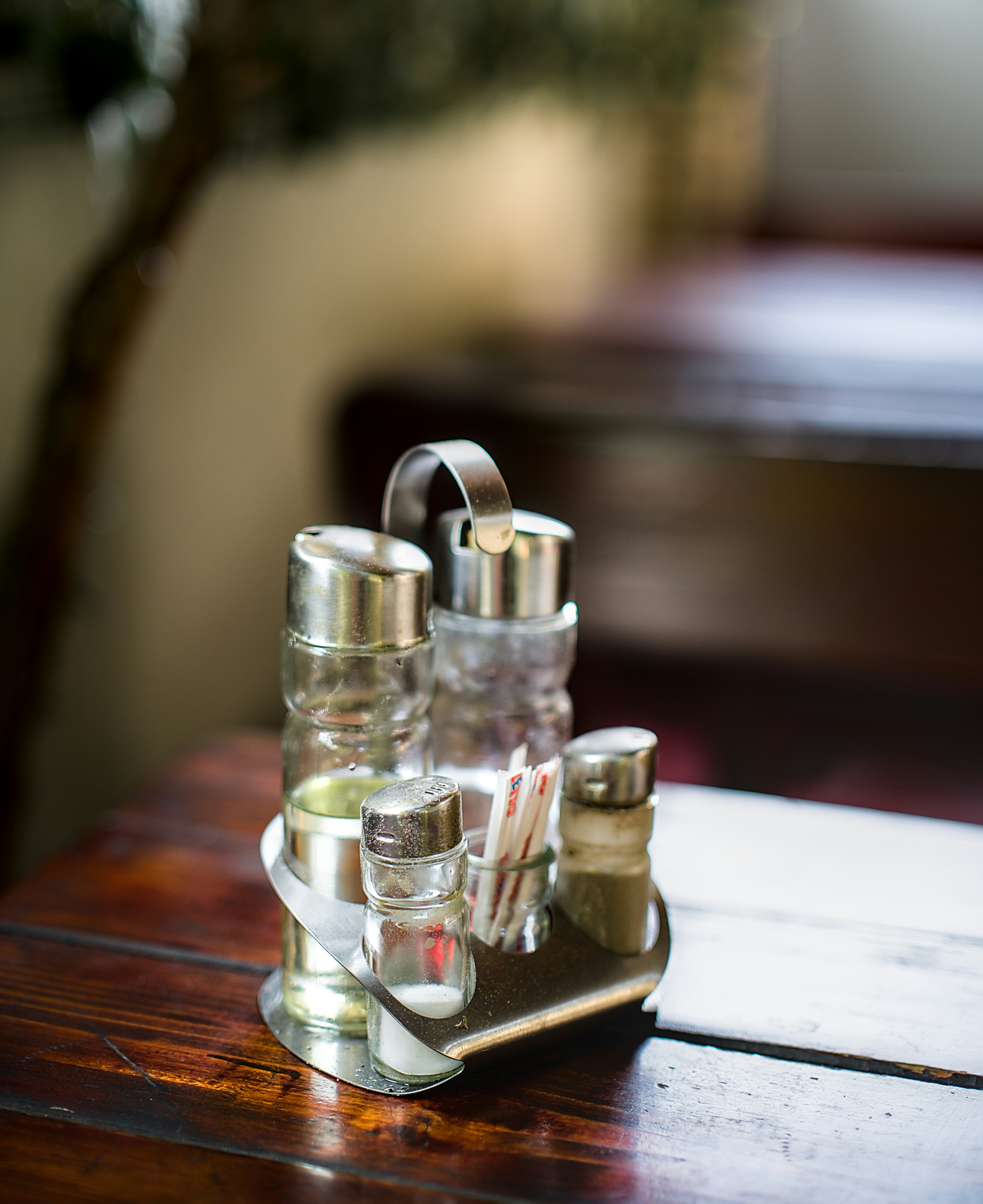 A condiment set rests on a wooden table.