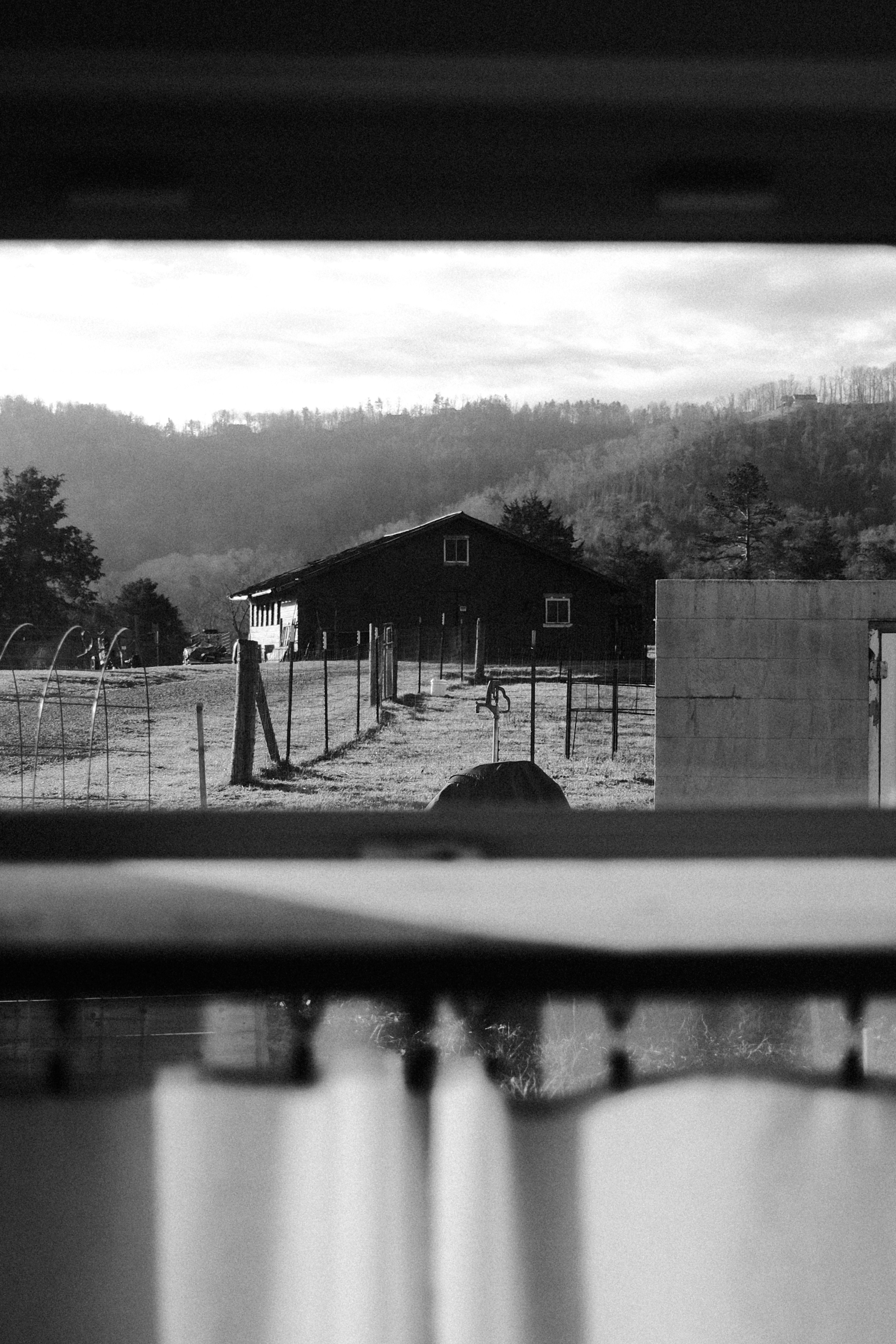 A farmhouse is framed by a window.