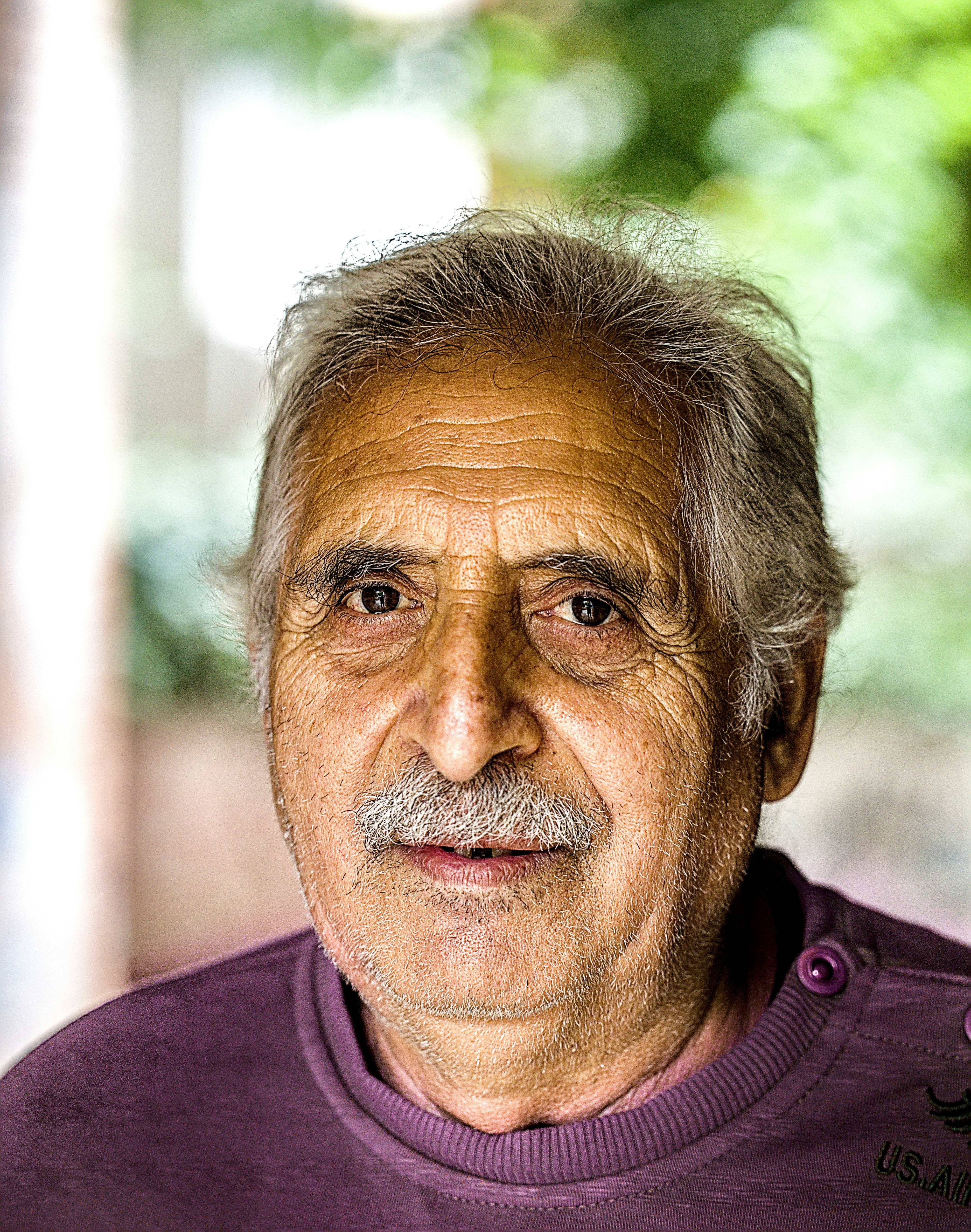 An older man with a mustache smiles gently.